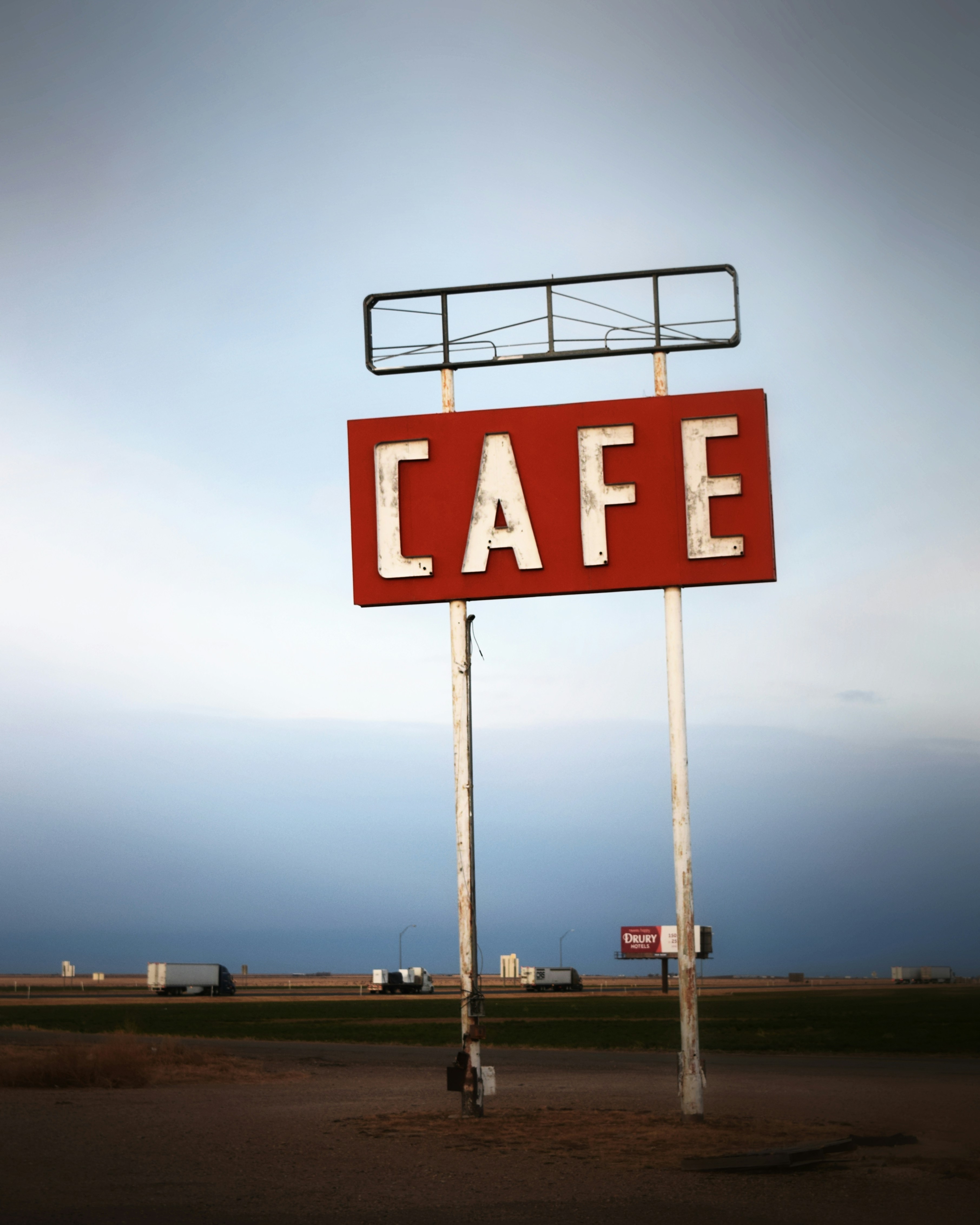 Rust-Red CAFÉ Sign Looms Over an Open Desert Highway