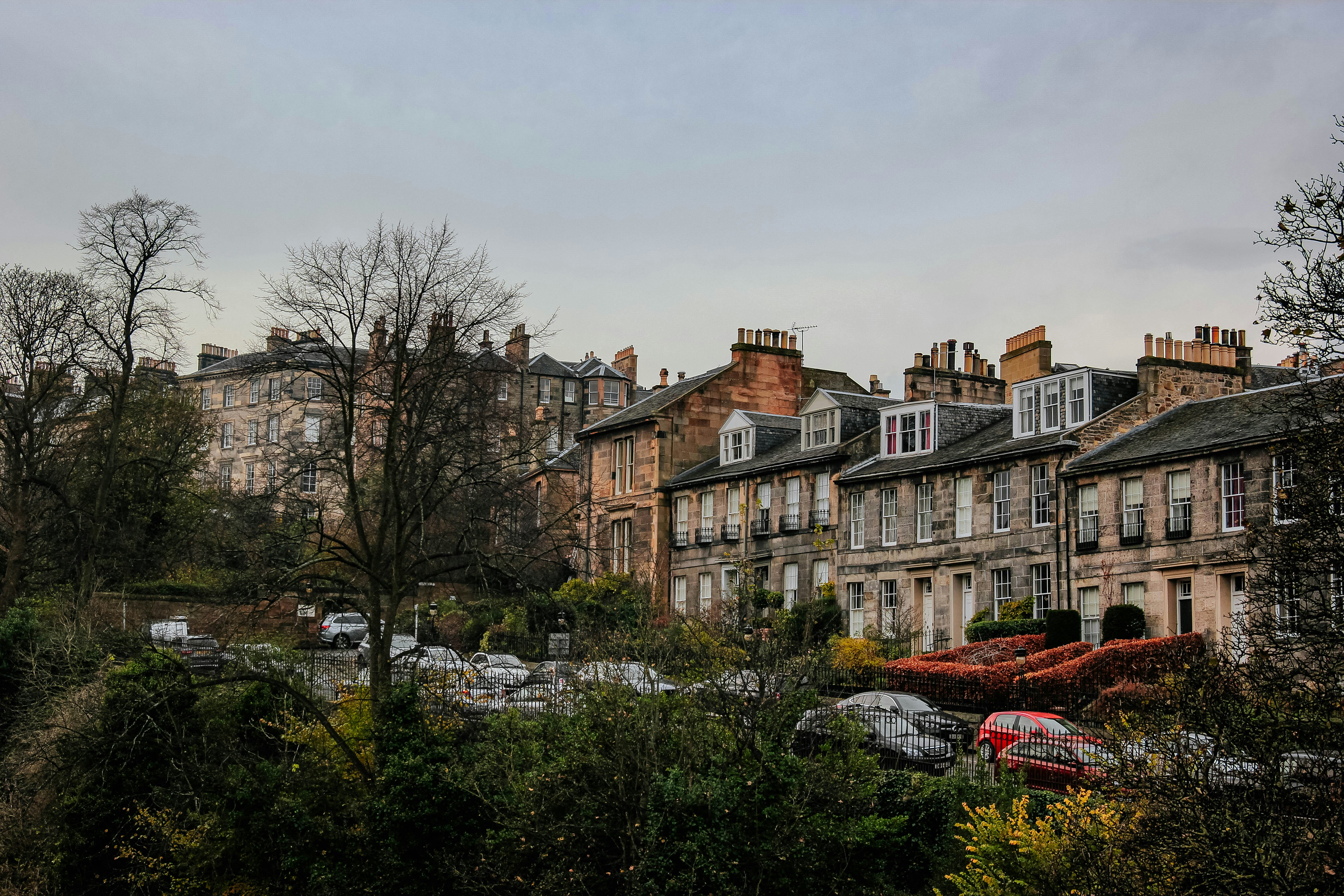 Charming row of historic townhouses nestled among lush greenery in an urban setting. The scene captures a tranquil moment in a bustling neighborhood.