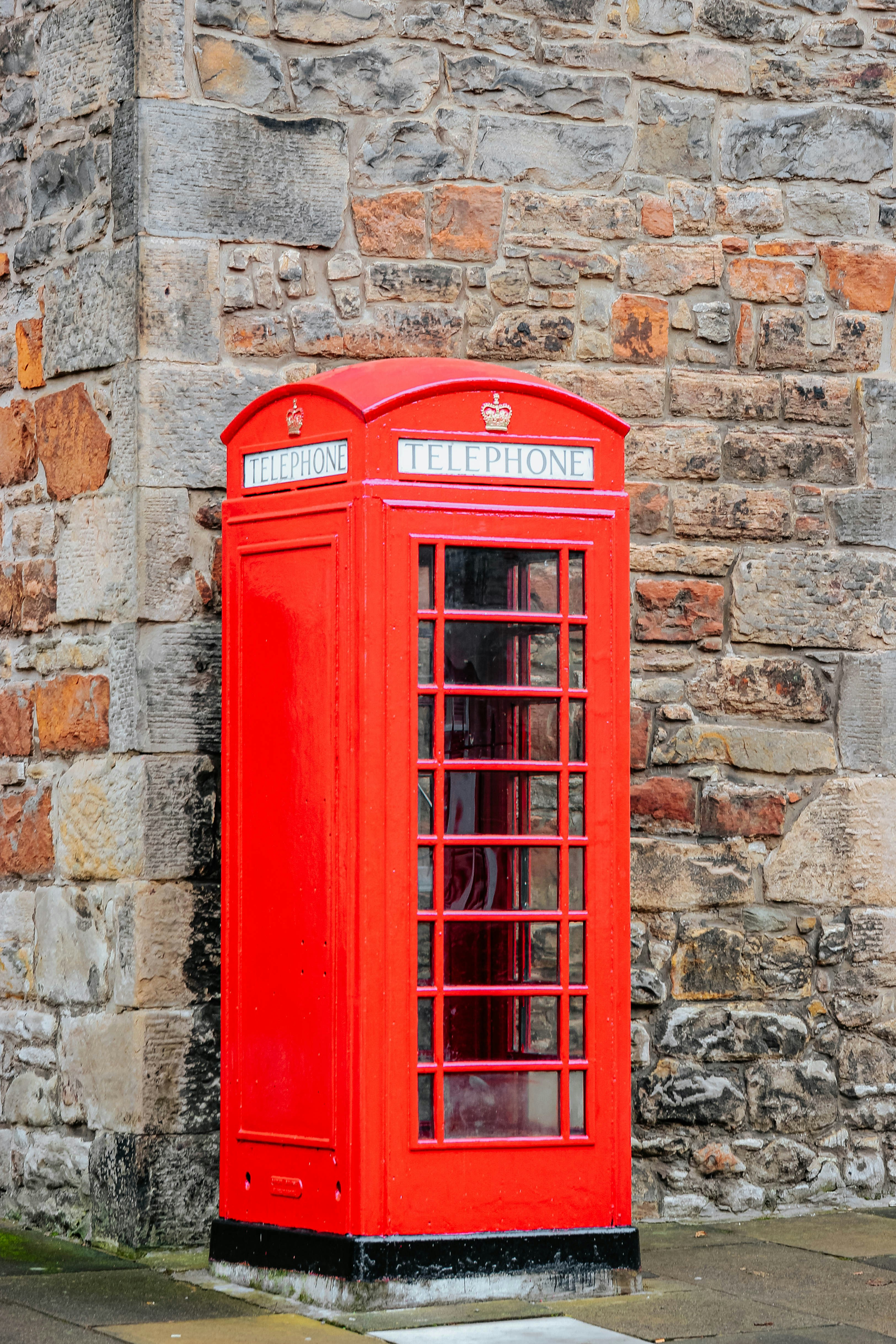 Crimson Kiosk Against a Weathered Stone Wall