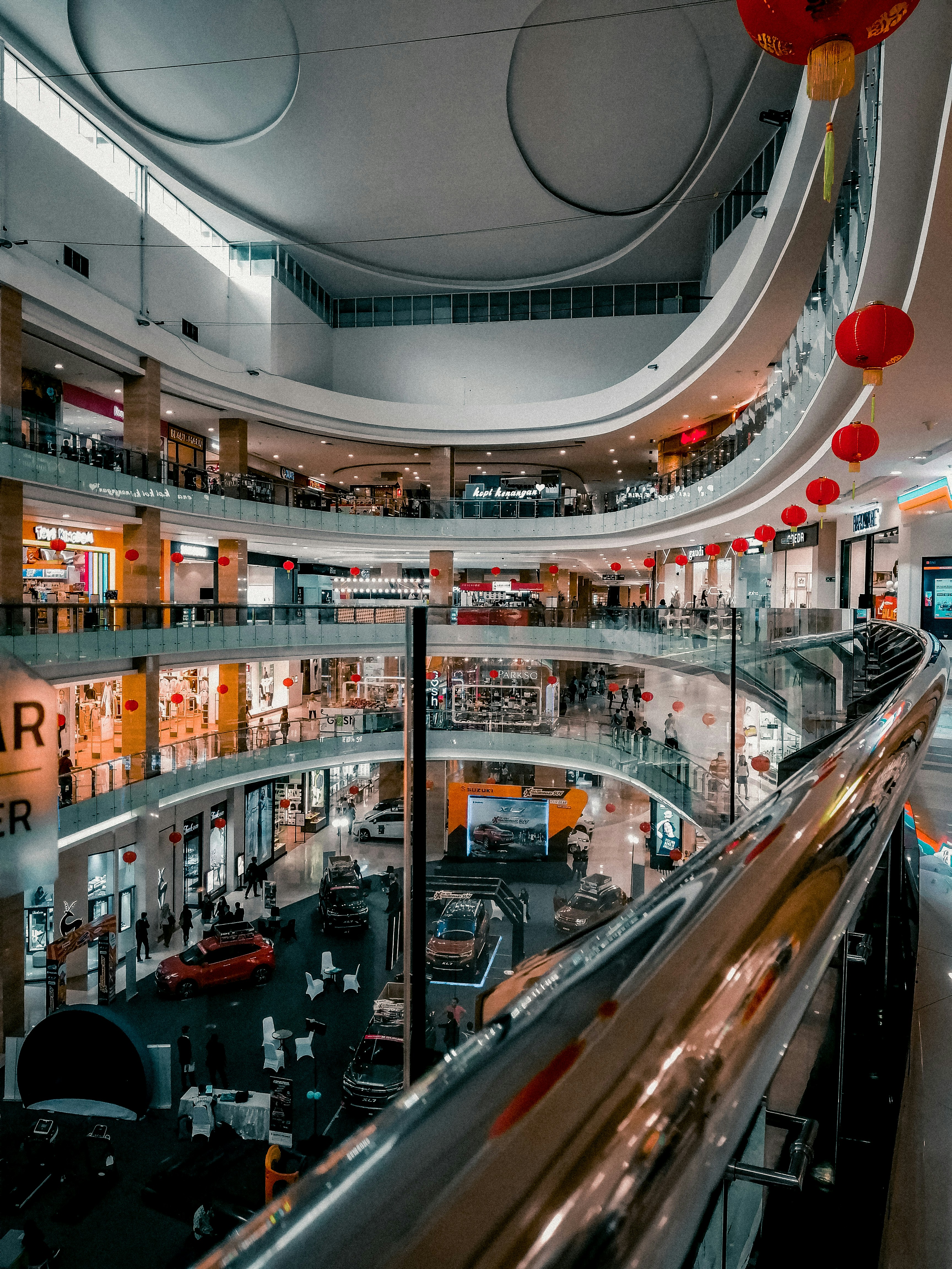 Vibrant shopping mall interior showcasing multiple levels, with decorative lanterns and a variety of stores visible. The scene captures the bustling atmosphere of urban commerce.