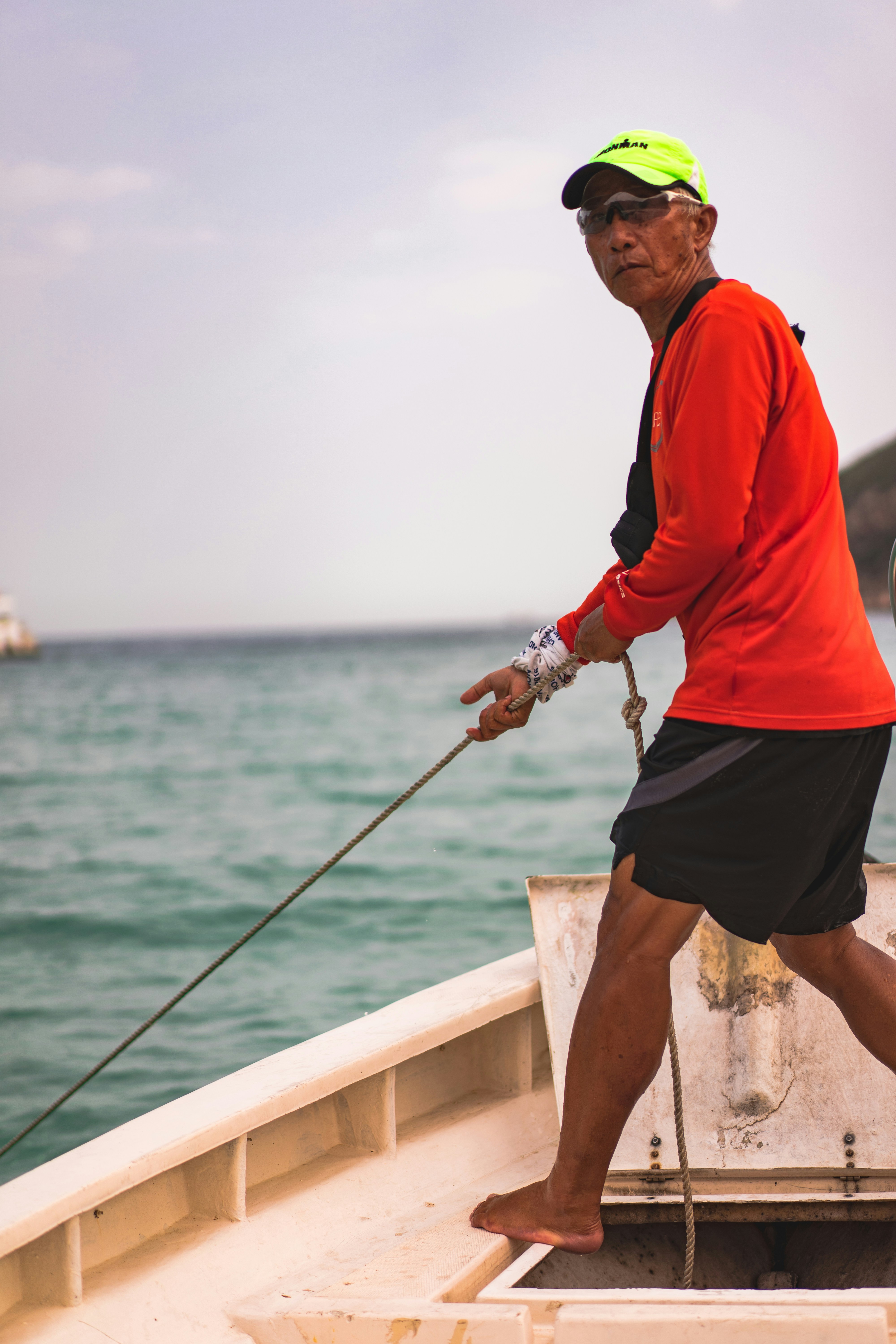 Bowline at Dawn: Neon-Capped Boatman Engaged with the Sea