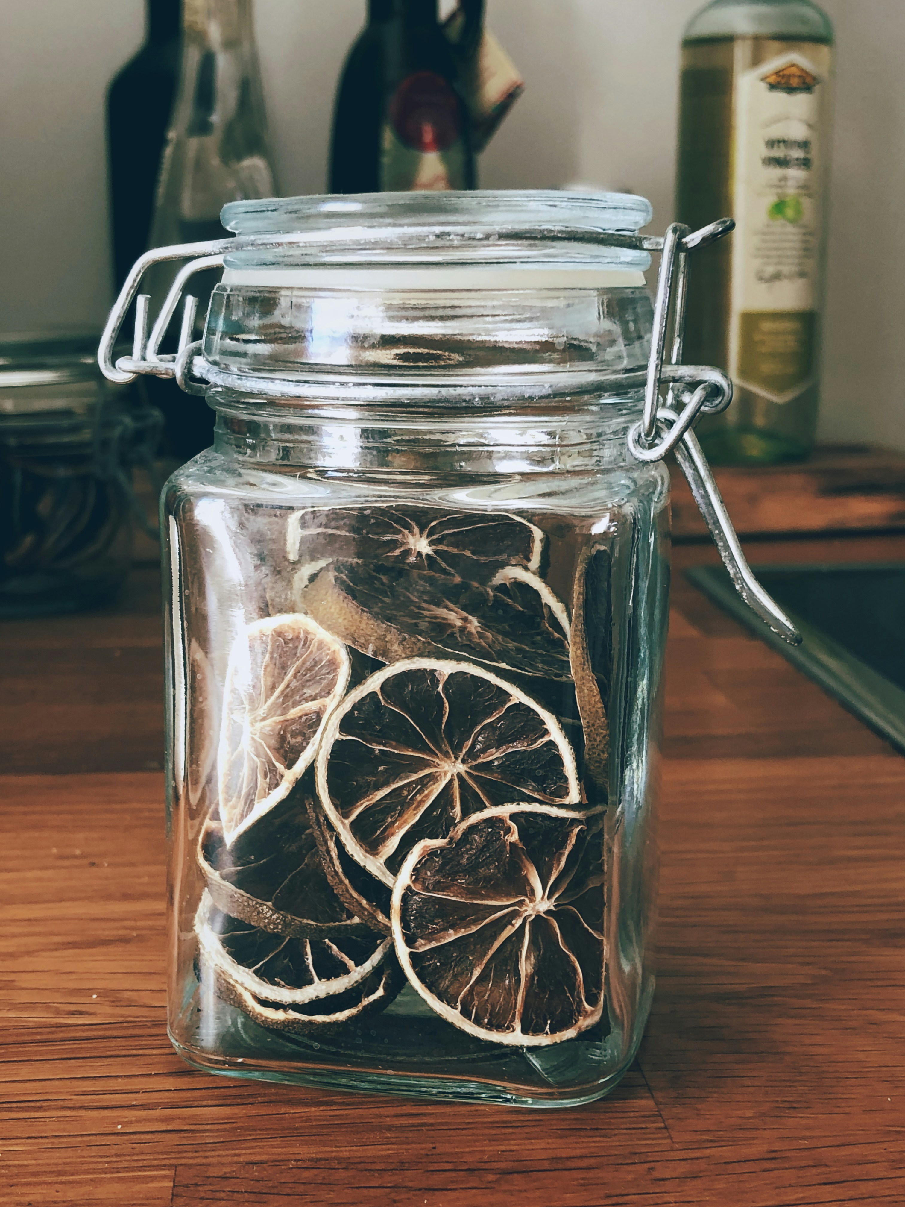 Dried lemon slices arranged neatly within a glass jar, showcasing their intricate textures and earthy tones.