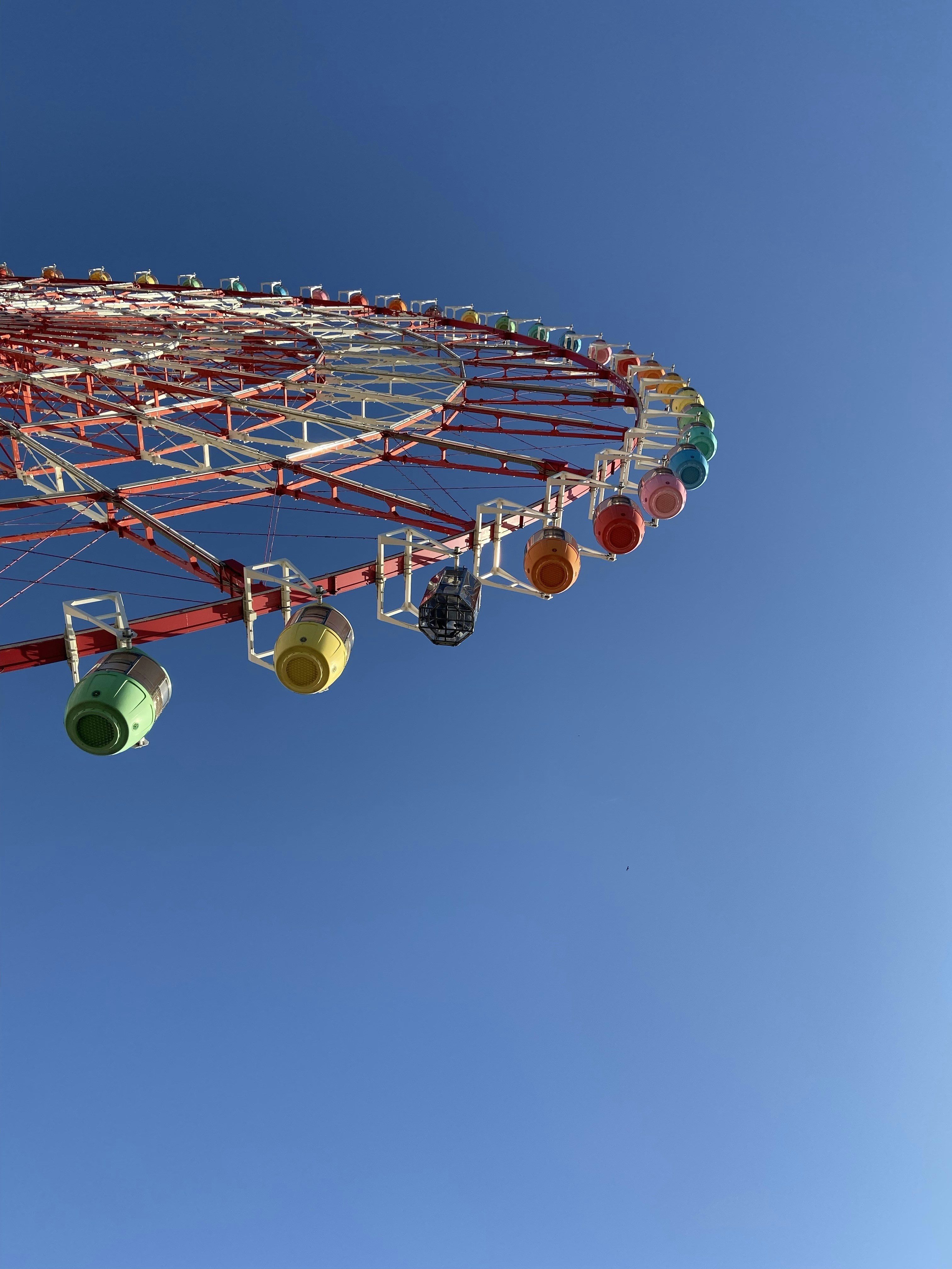 A vibrant Ferris wheel adorned with colorful gondolas against a clear blue sky, showcasing its intricate structure and playful design.