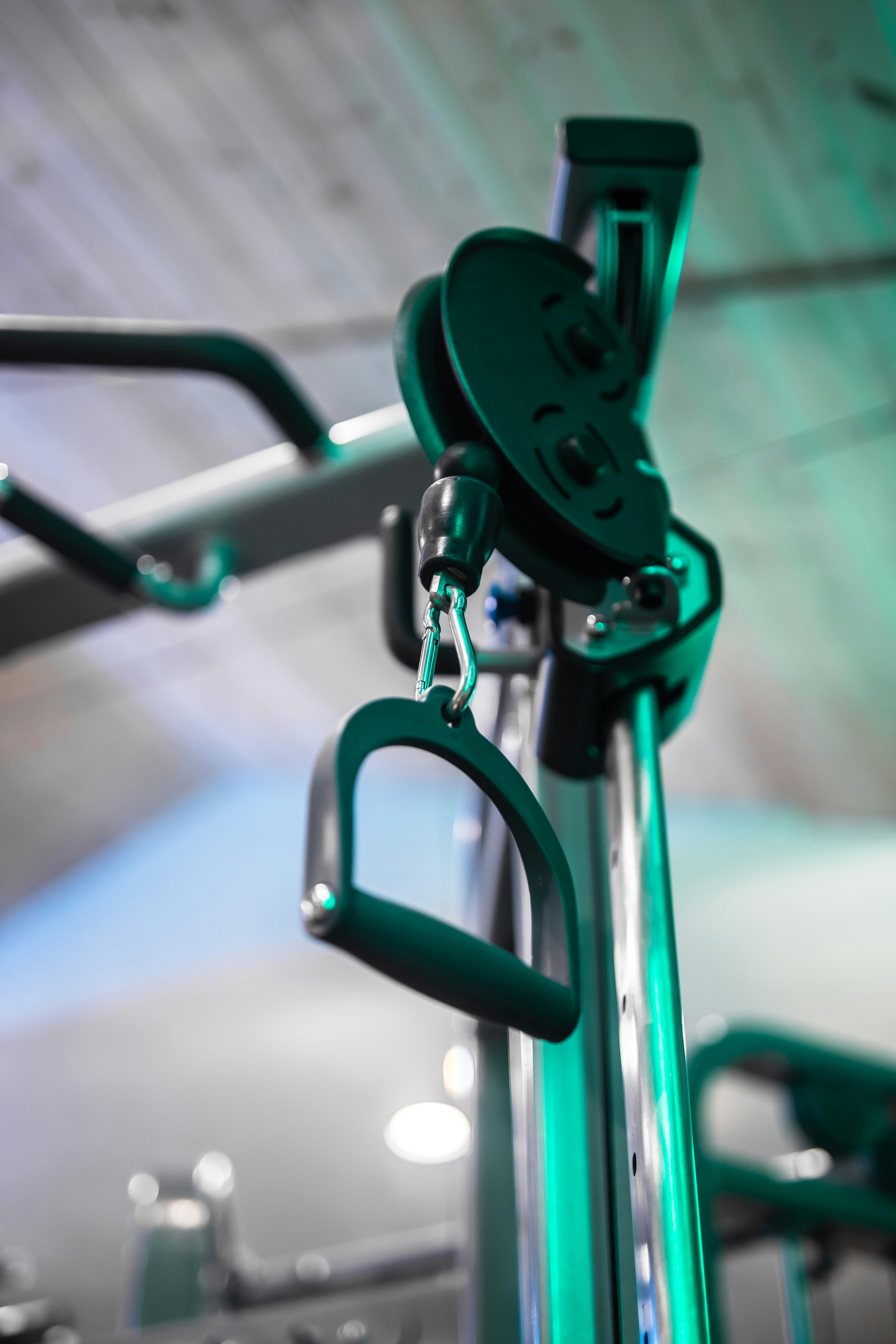 Industrial rig in teal glow: a climbing handle and pulley under soft bokeh