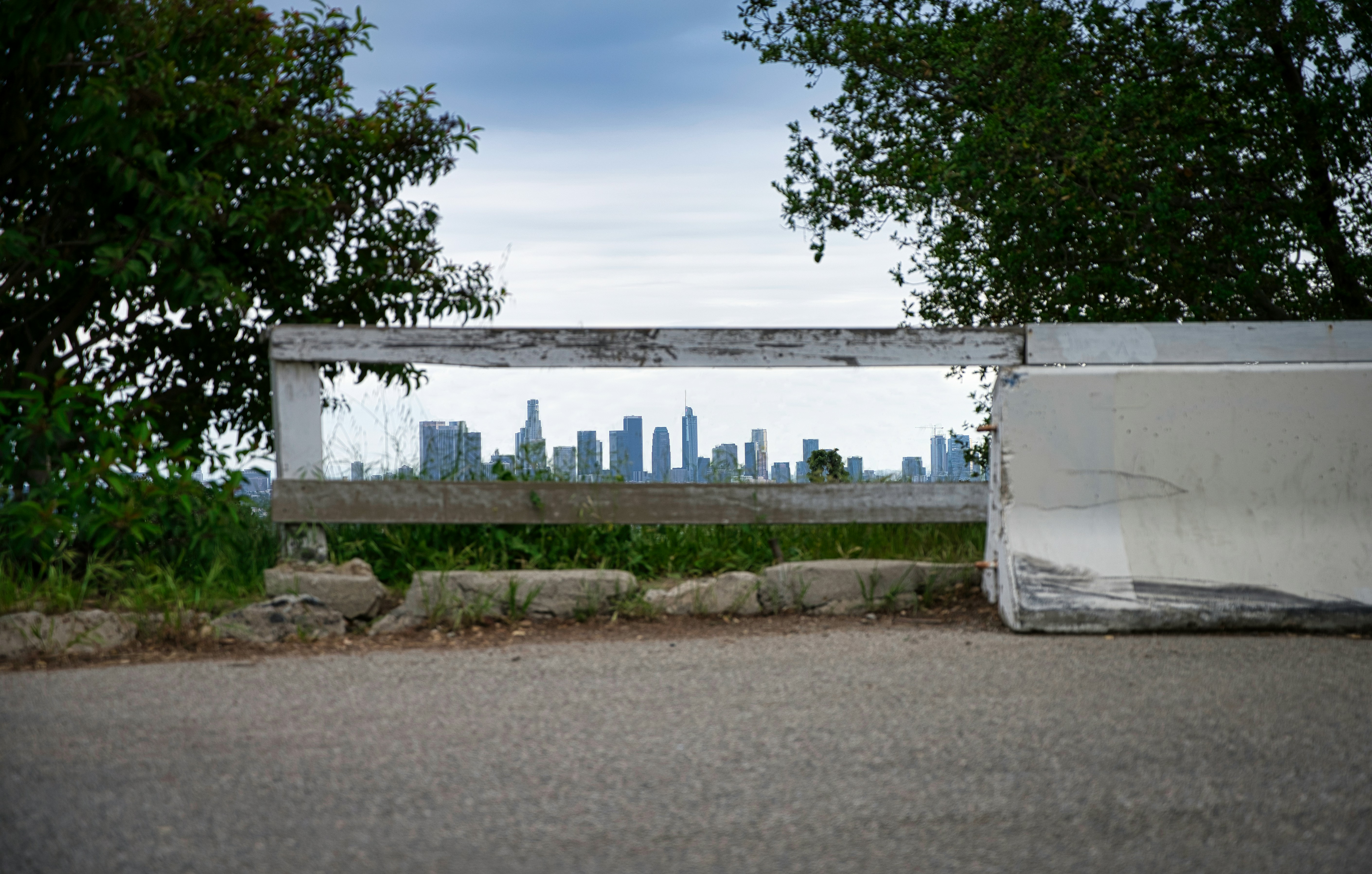 Through the Gap: City Skyline Framed by a Weathered Barrier