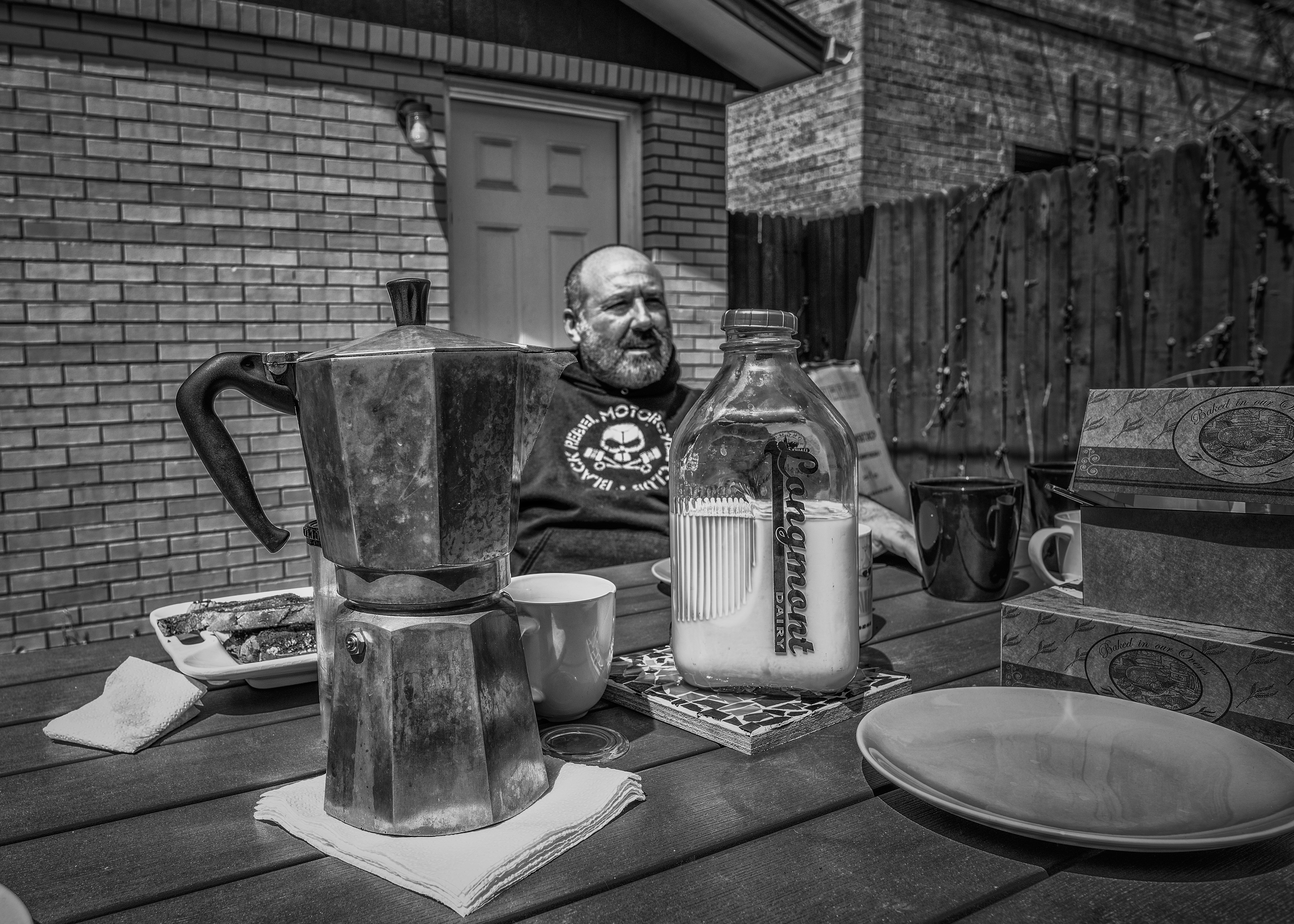 Grayscale photo of man sitting on chair near table with pitcher and ...