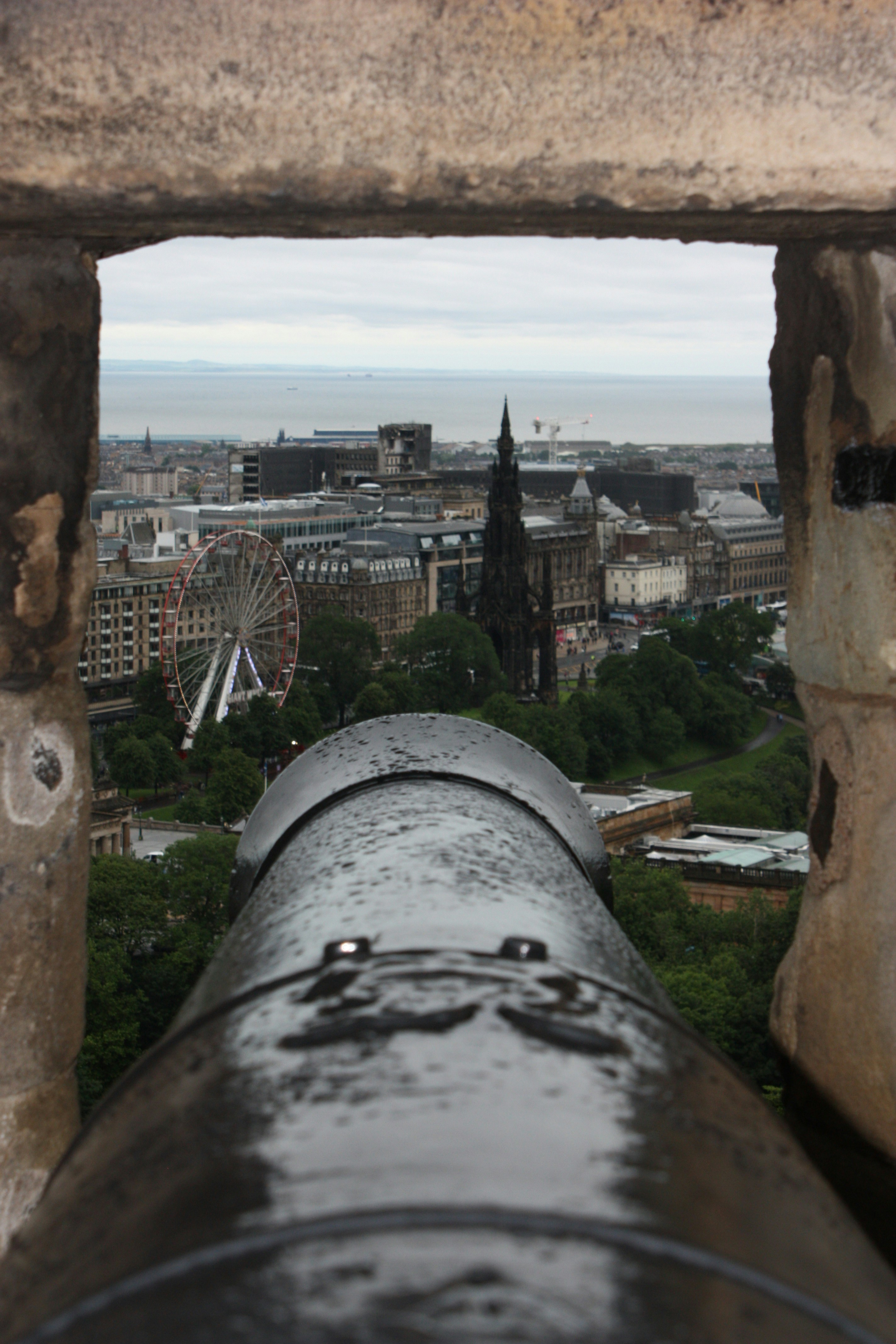 Fortress Gaze: The Cannon's Barrel Framing a City Crowned by a Ferris Wheel