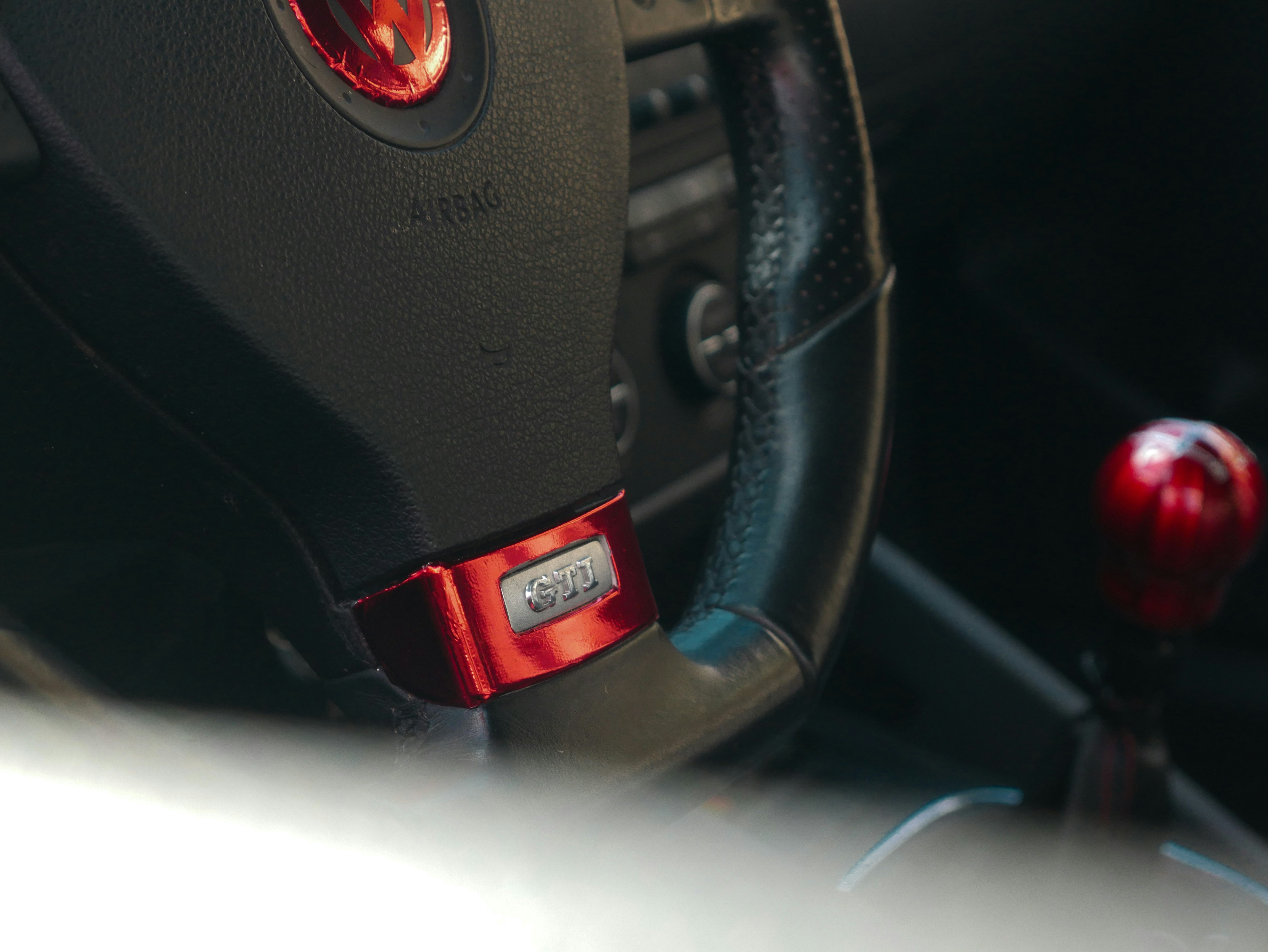 Close-up of a Volkswagen Golf GTI steering wheel with a red metallic detail and matching gear shift knob.