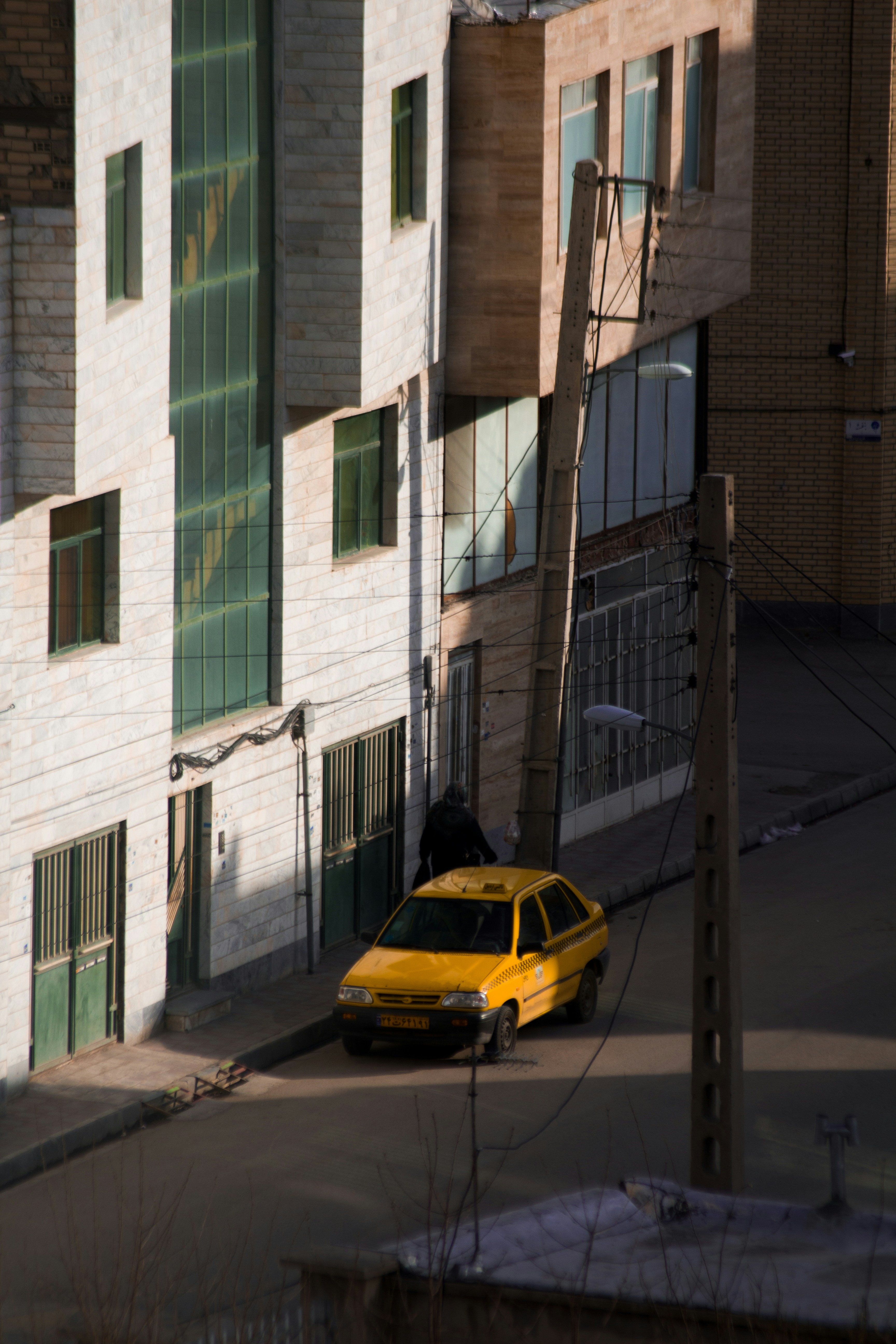 Yellow Taxi Quietly Anchored Along a Sunlit Building