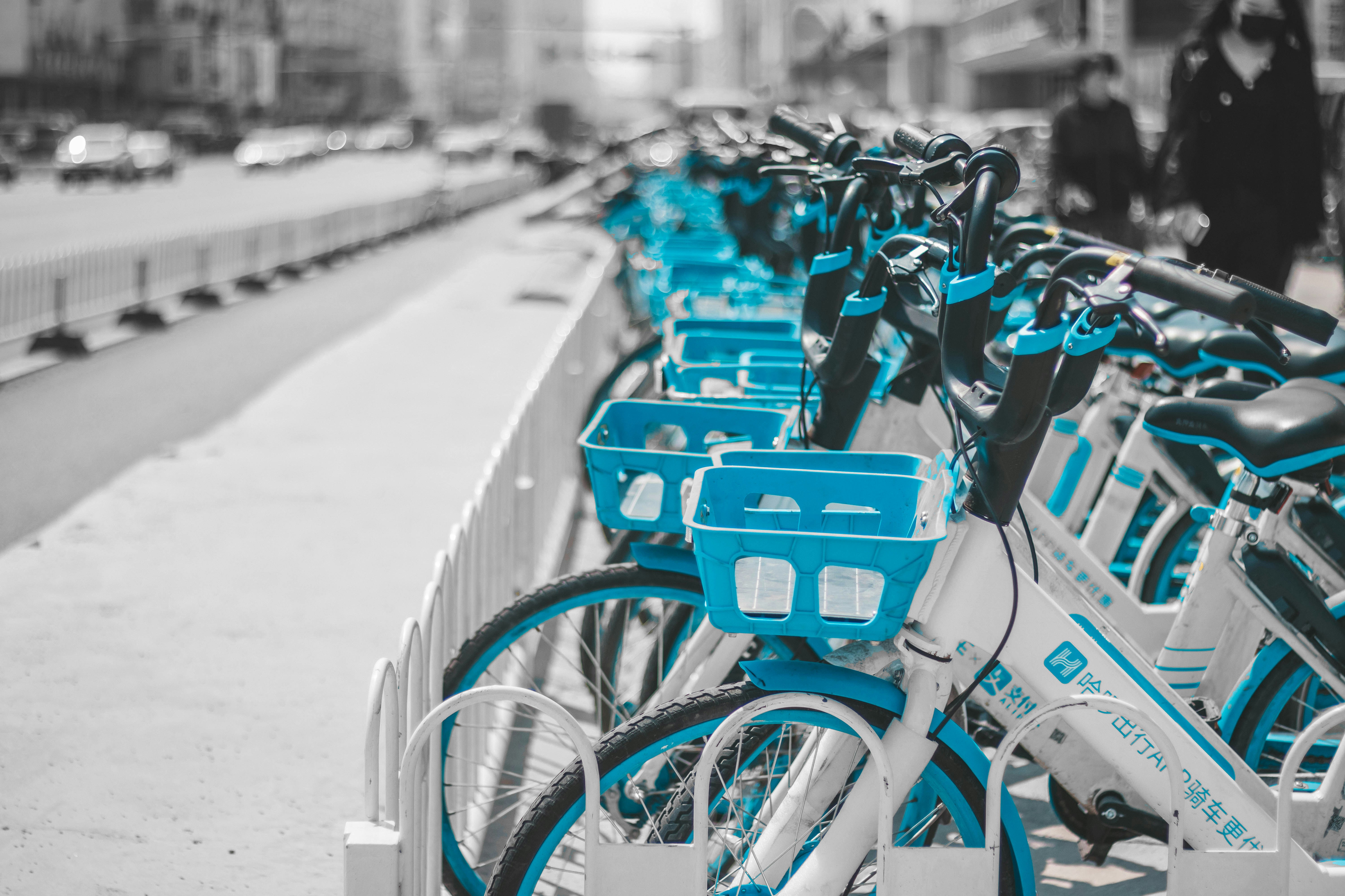 Row of blue and white rental bicycles lined up on a city street.