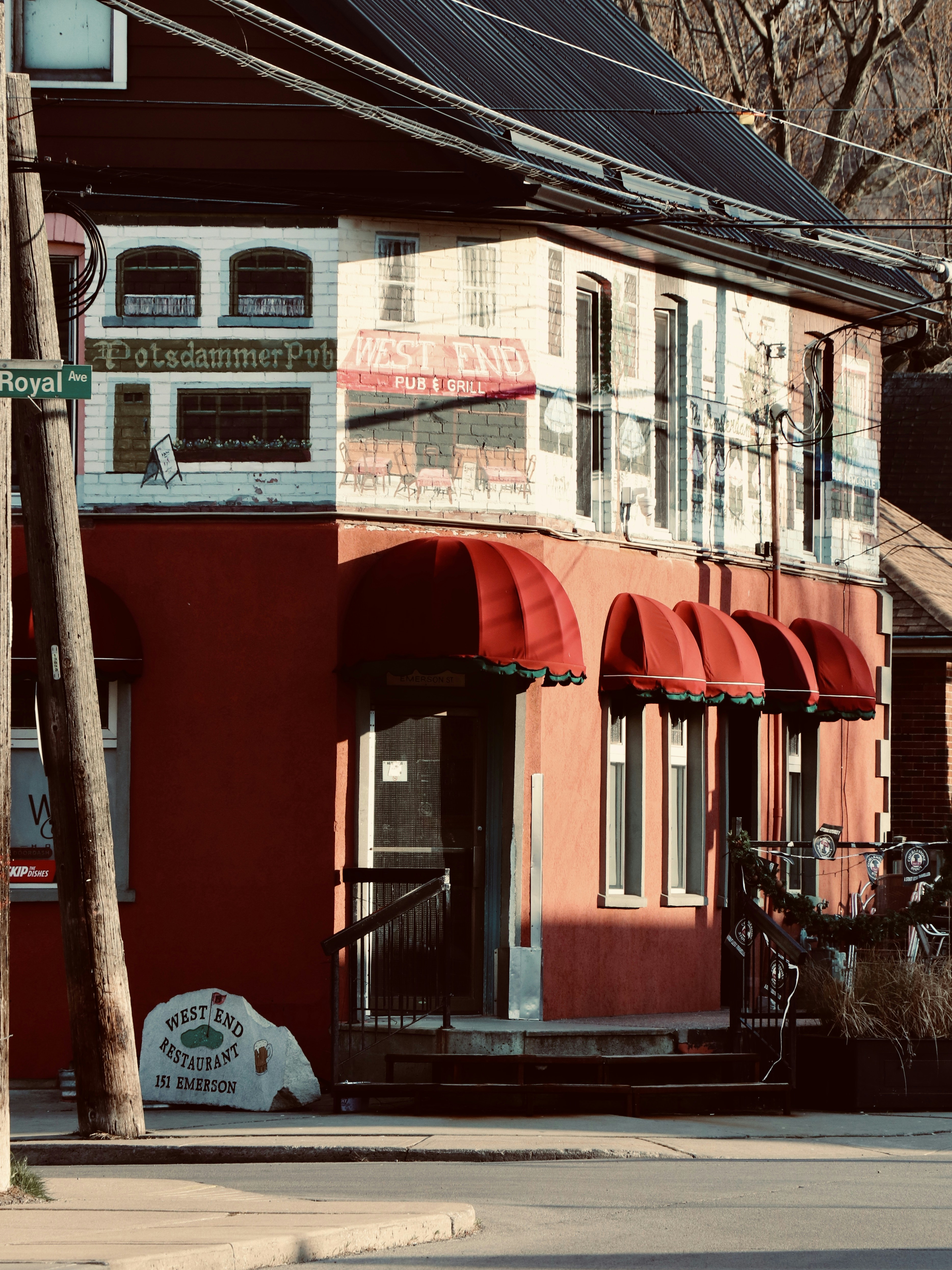 Quaint restaurant exterior featuring red awnings and vintage signage, set against a backdrop of urban architecture.