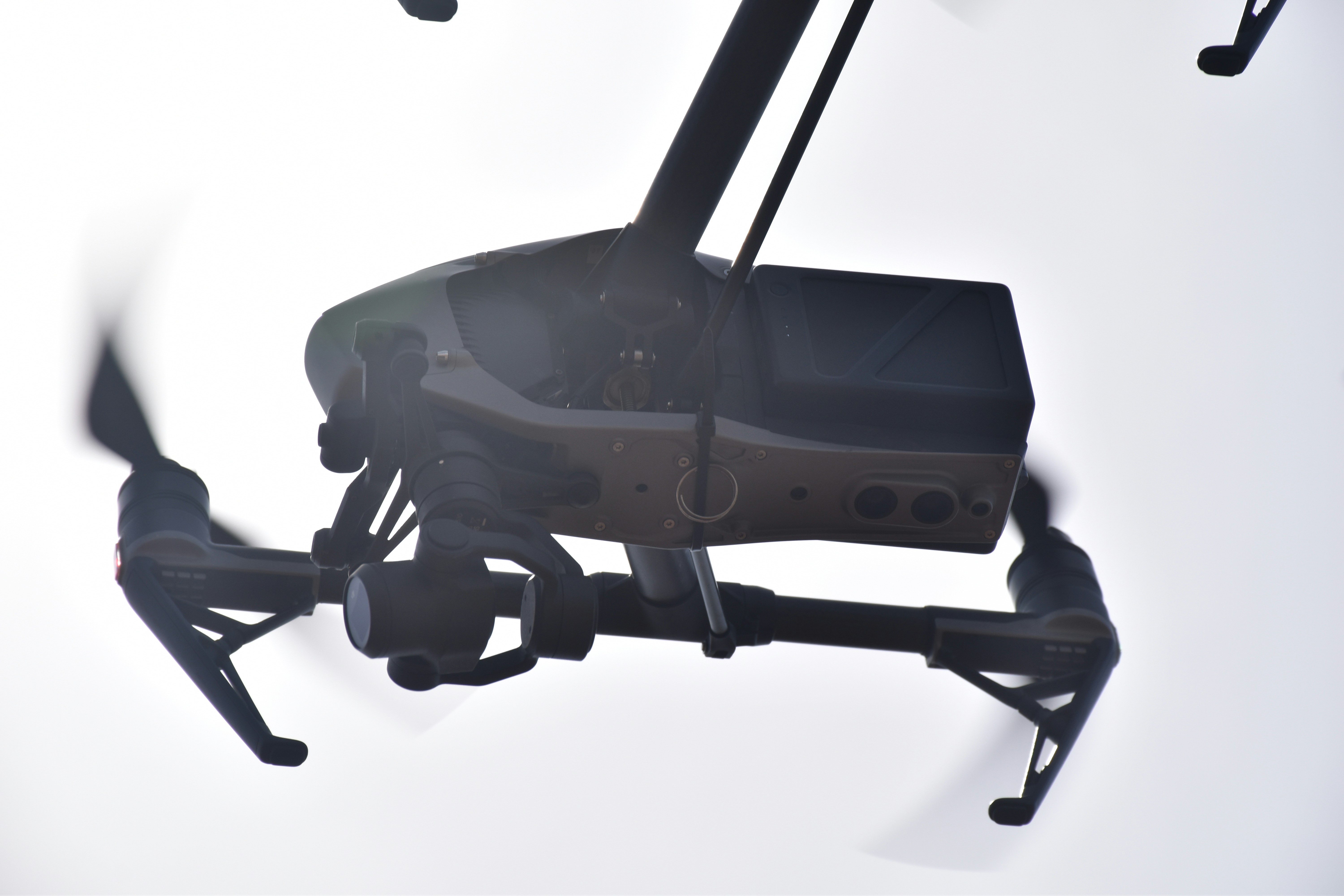 Midflight silhouette: a compact drone gliding against a bright sky