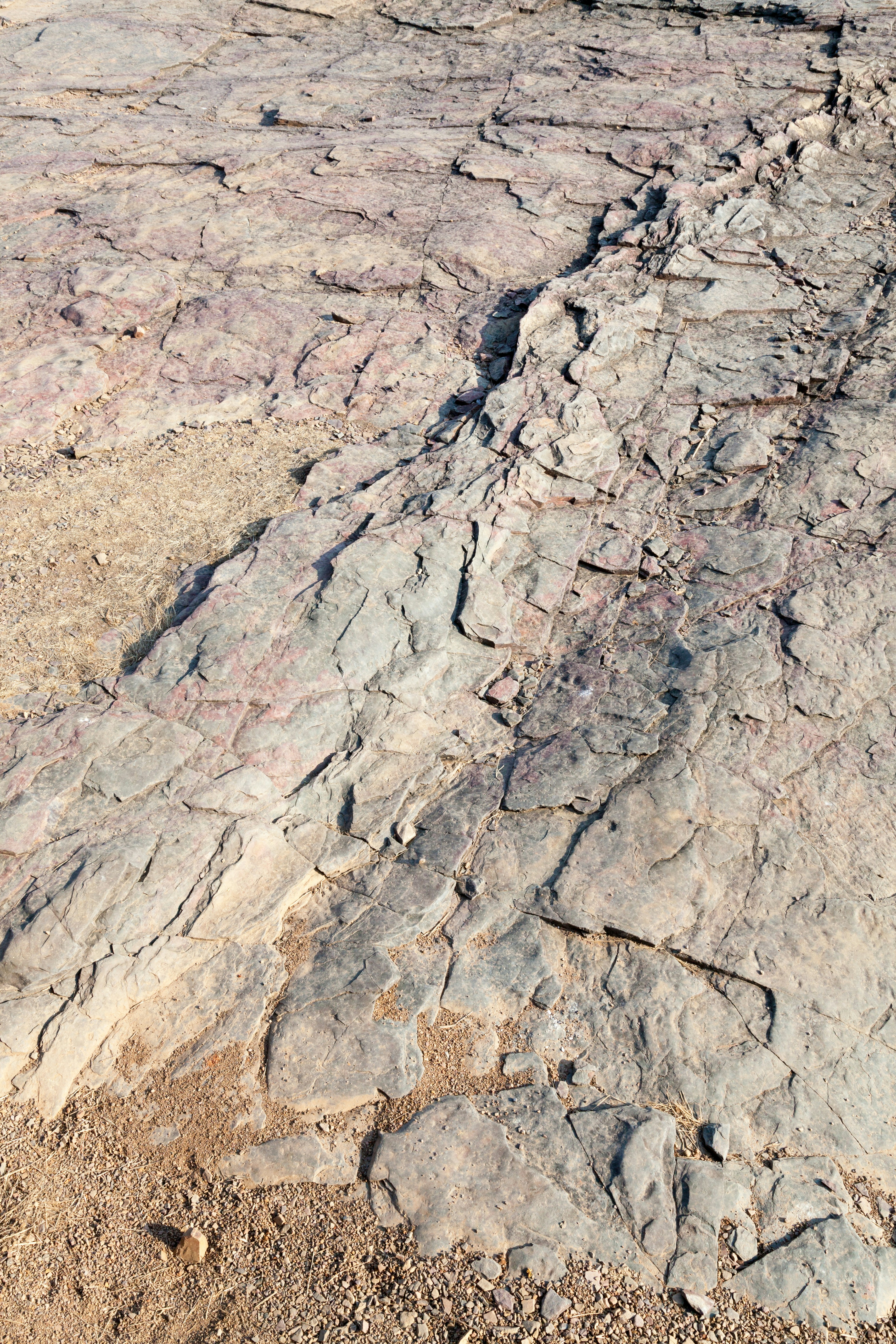 Intricate patterns of weathered rock formations revealing layers of geological history in a sunlit landscape.