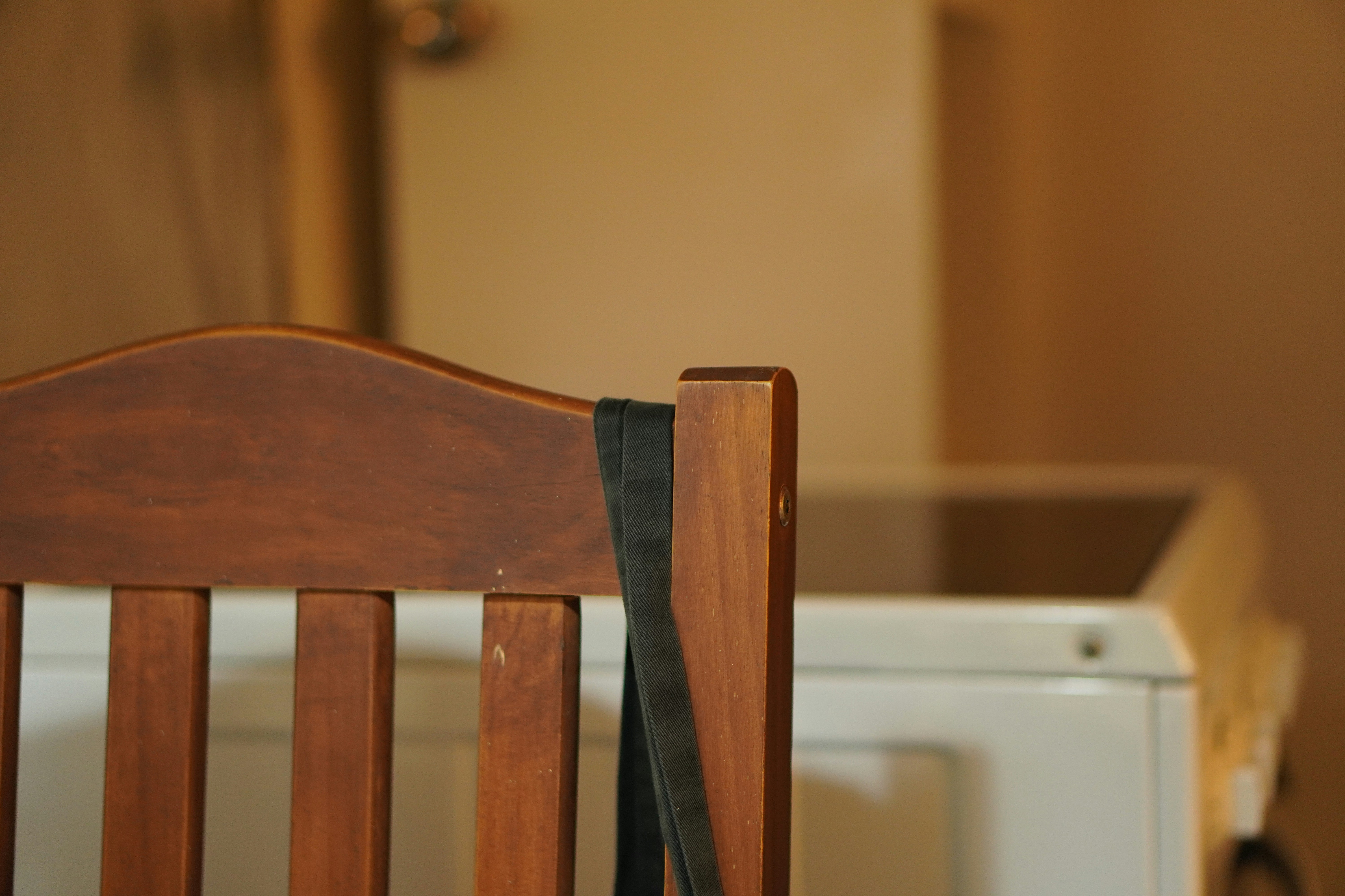 Strap Draped Across a Wooden Chair in a Quiet, Warm Interior