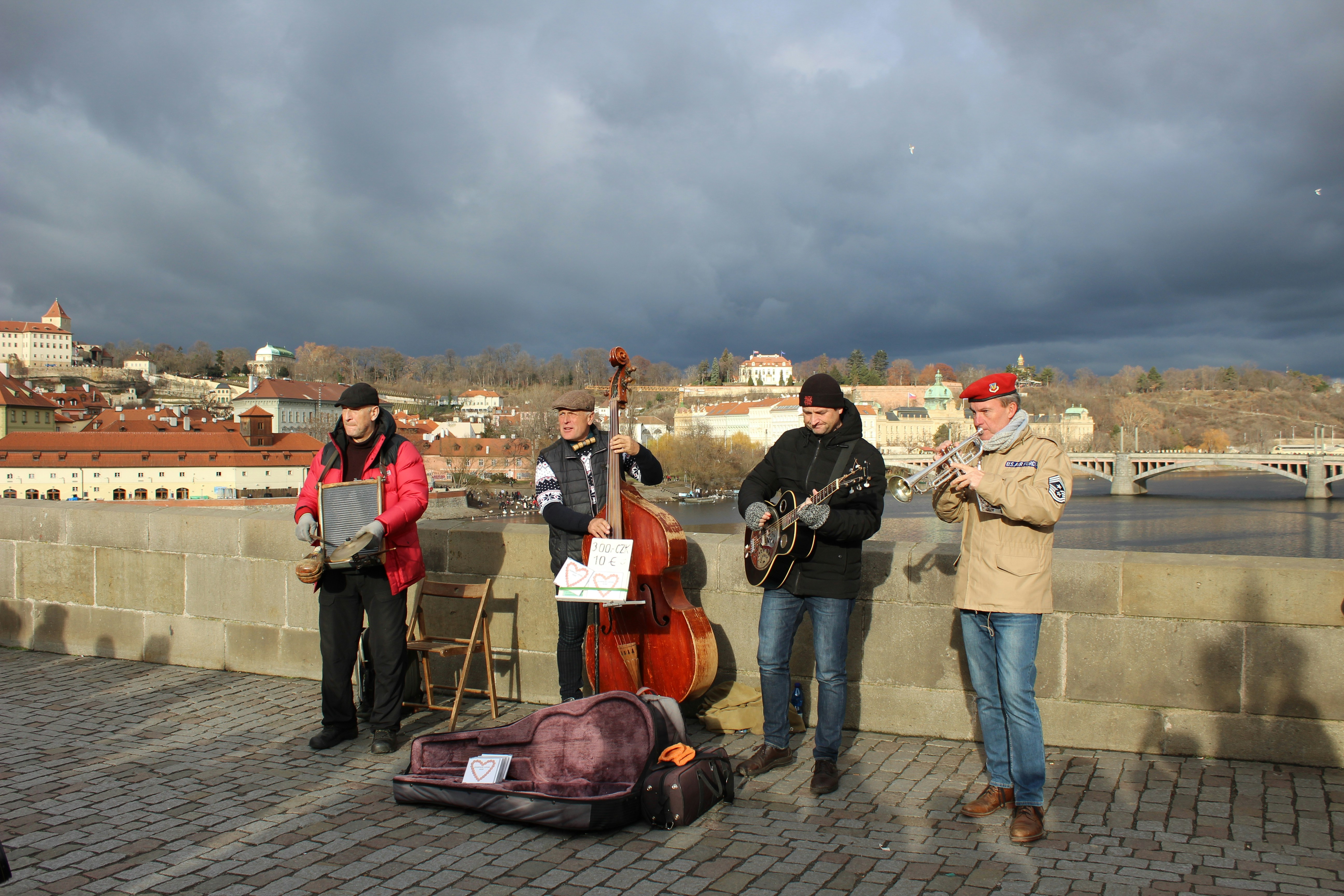 Street musicians performing on a historic bridge under a cloudy sky.