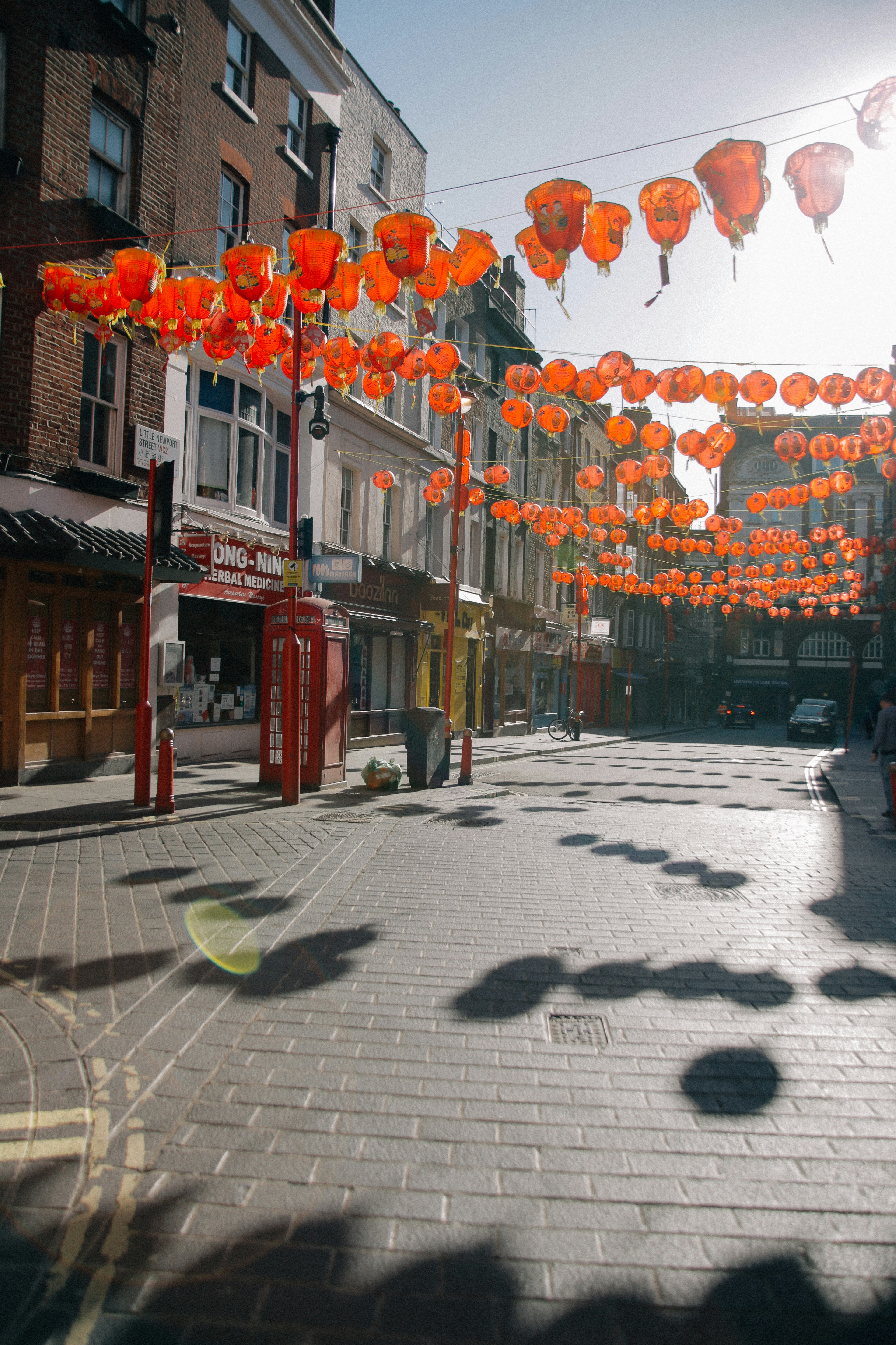 Red Lantern Alley: A Sunlit City Street Draped in Floating Orbs
