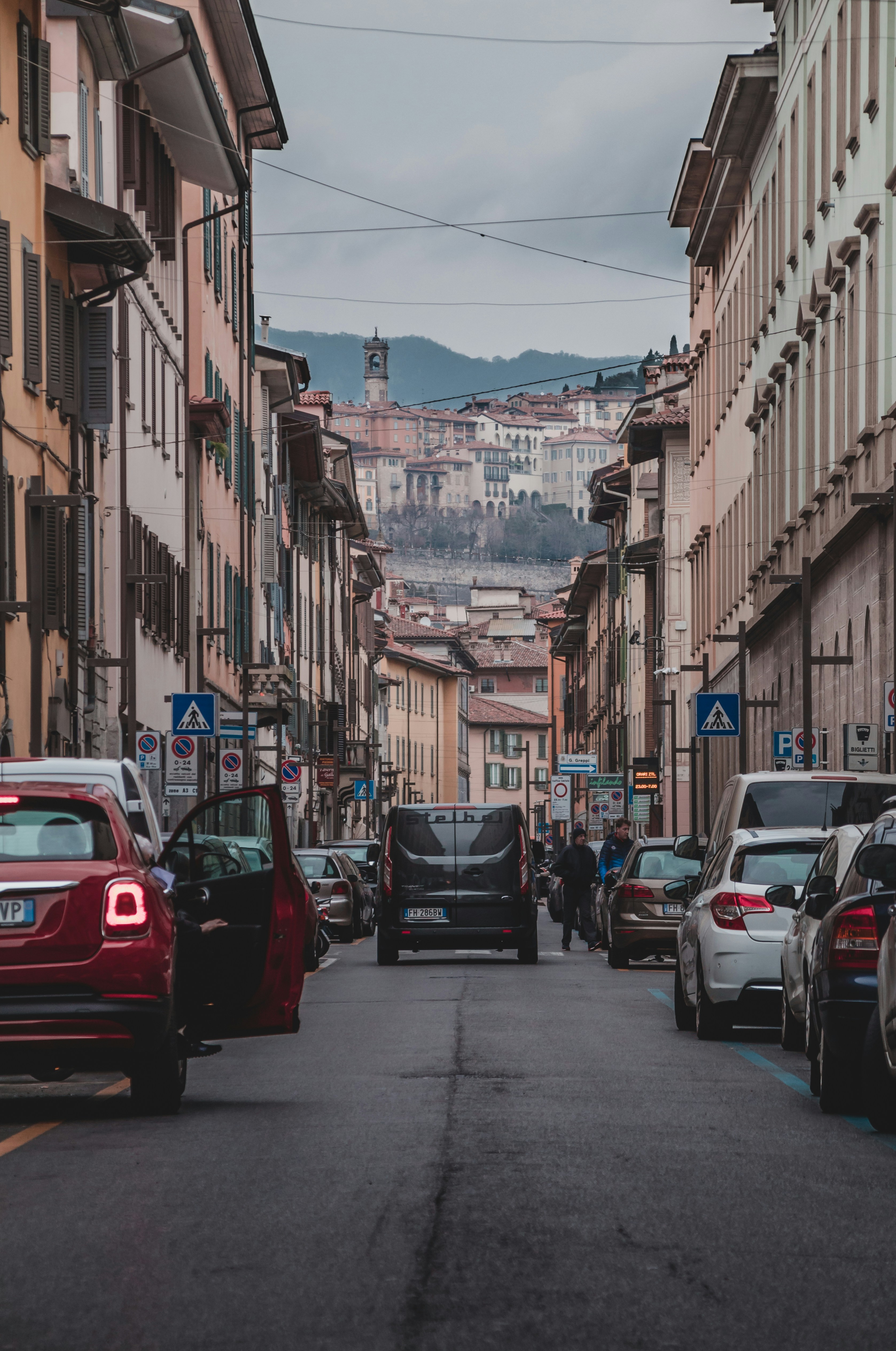 A Quiet Perspective: Cars and Colored Facades Down a Narrow Italian Street