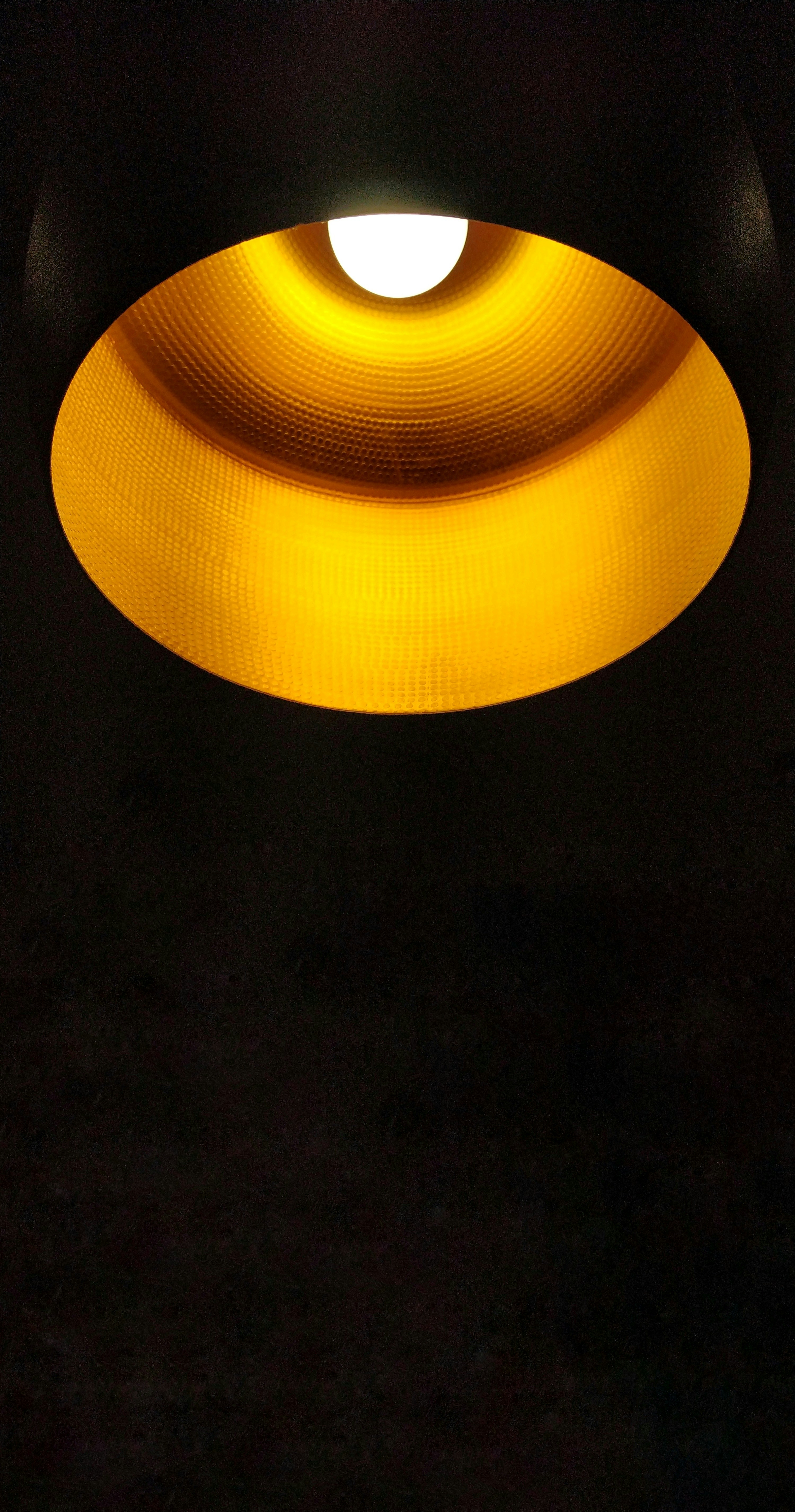 A warm, glowing pendant light casts a soft amber hue, contrasting against the dark background. The intricate design of the lampshade enhances the visual appeal.