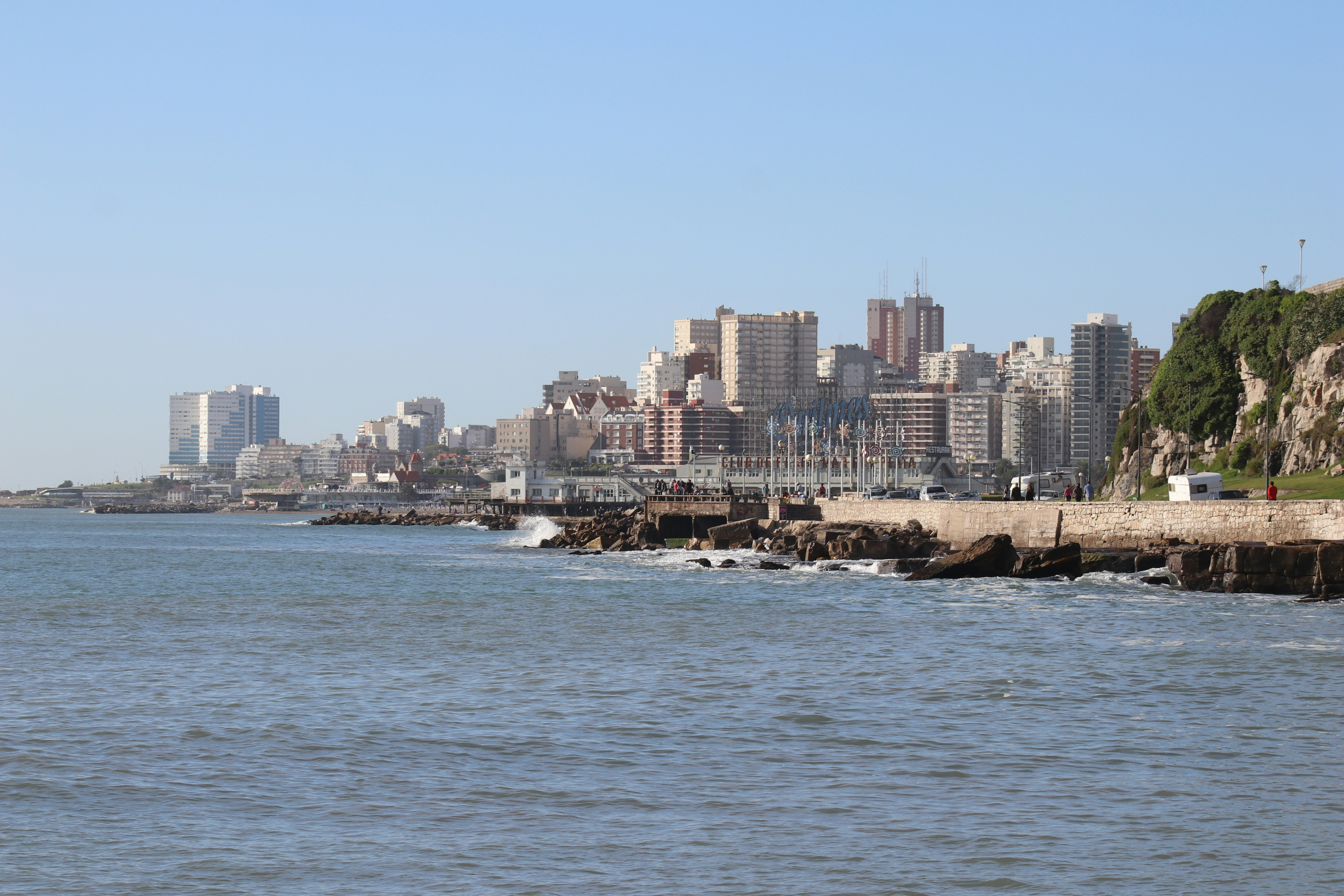 Urban skyline along the coastline under a clear blue sky.