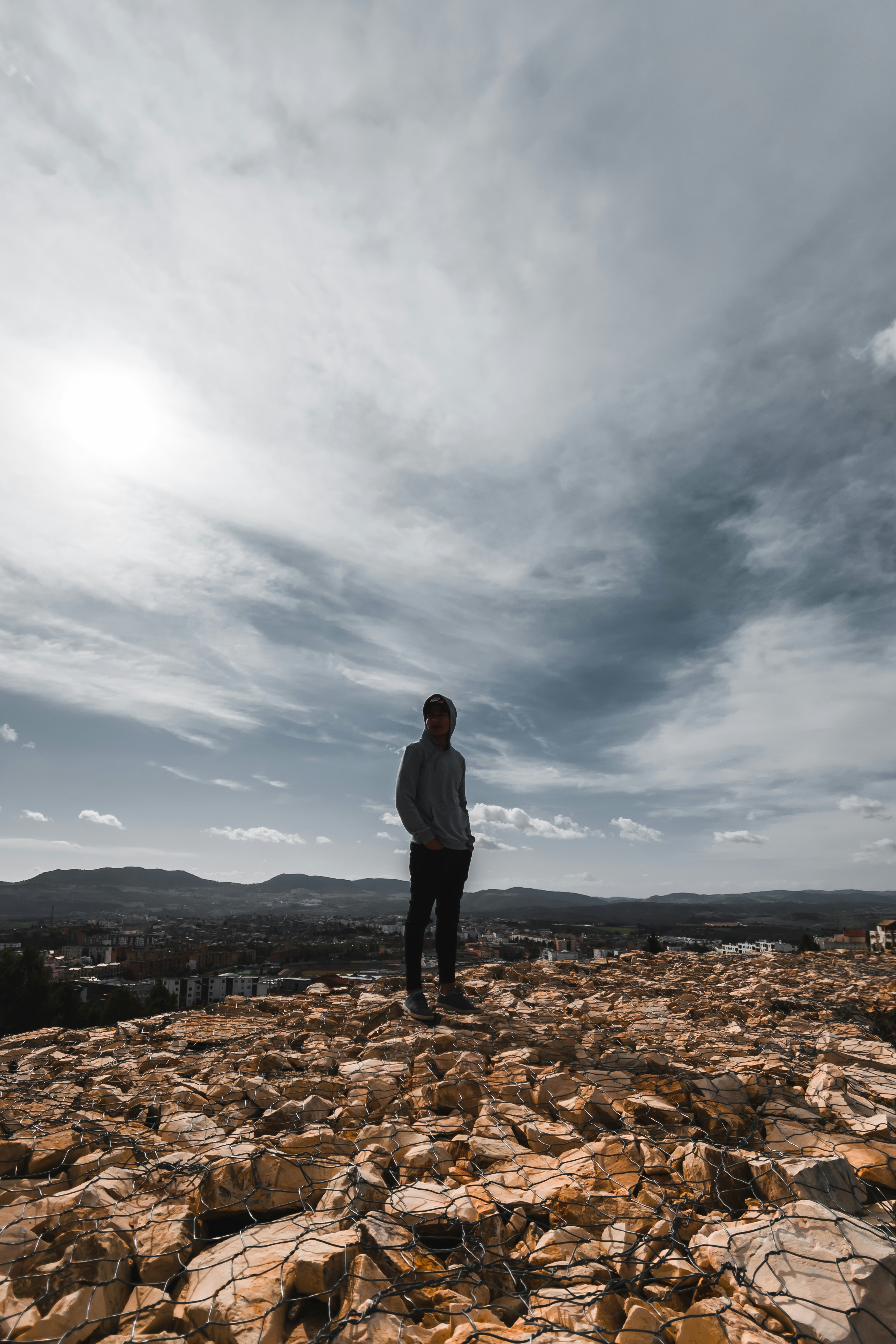 man in white shirt standing on brown field under gray cloudy sky during daytime
