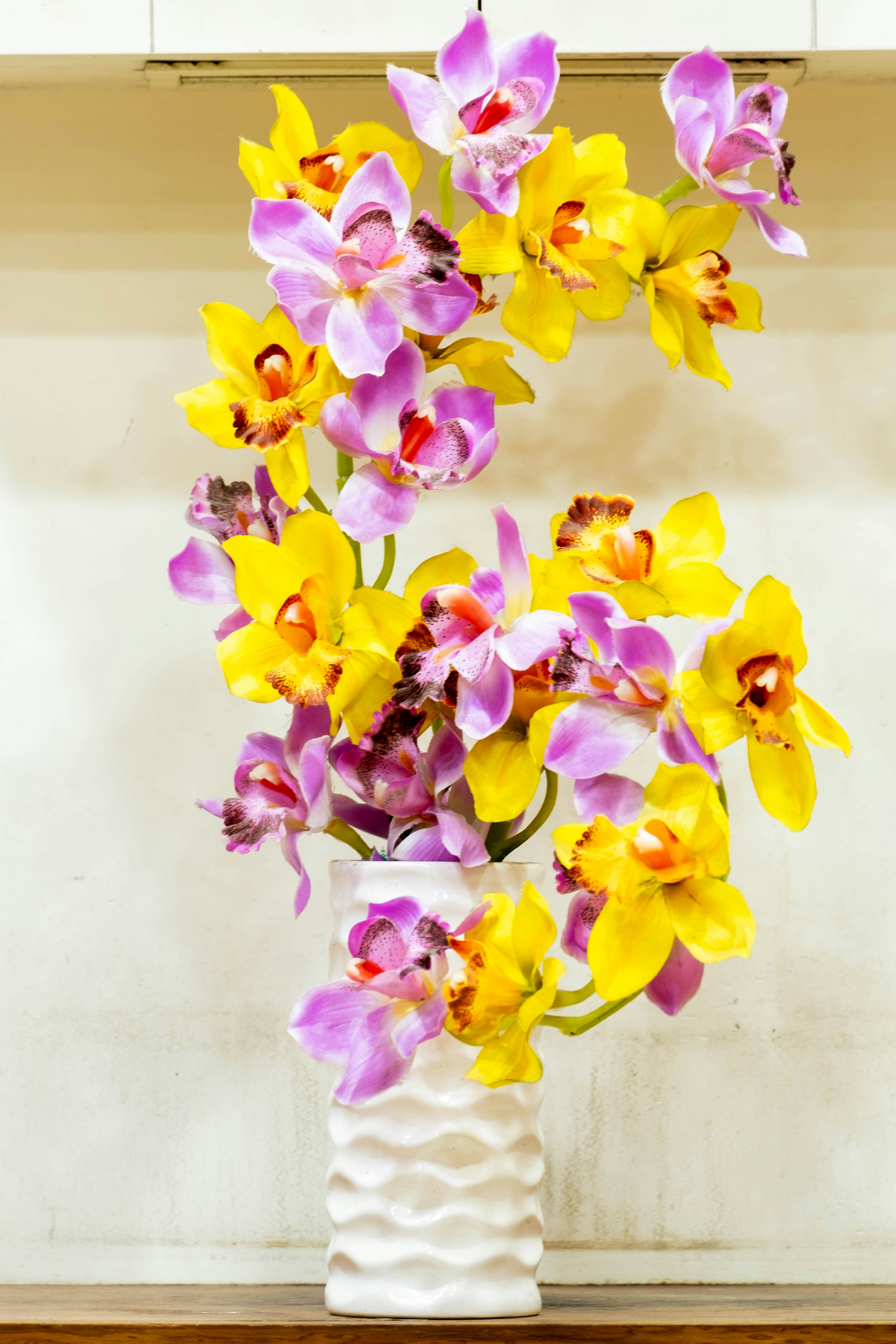 Vivid Orchid Bouquet: Yellow and Purple Blooms in a Textured White Vase