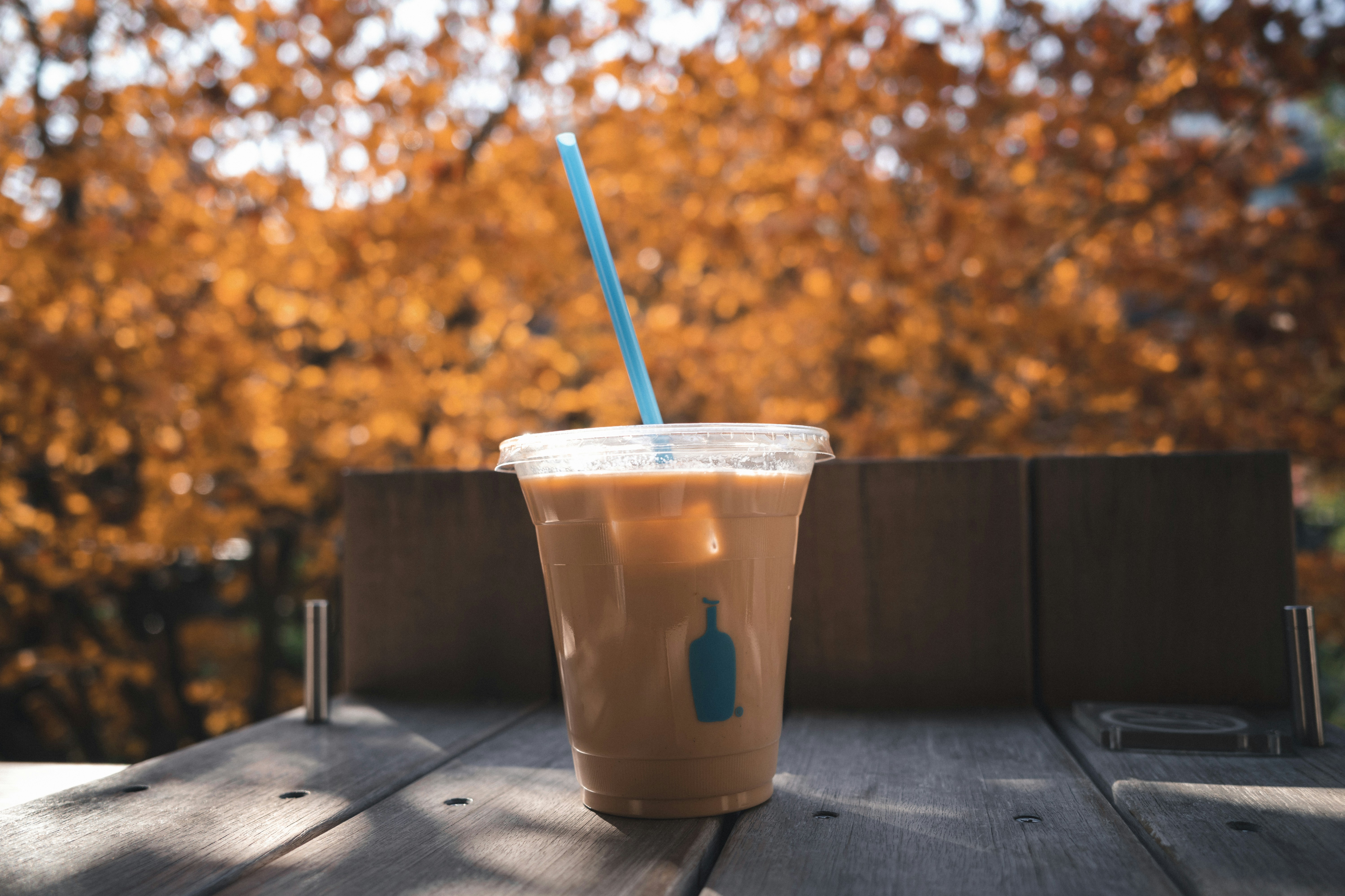 White and blue disposable cup with straw on brown wooden table photo ...