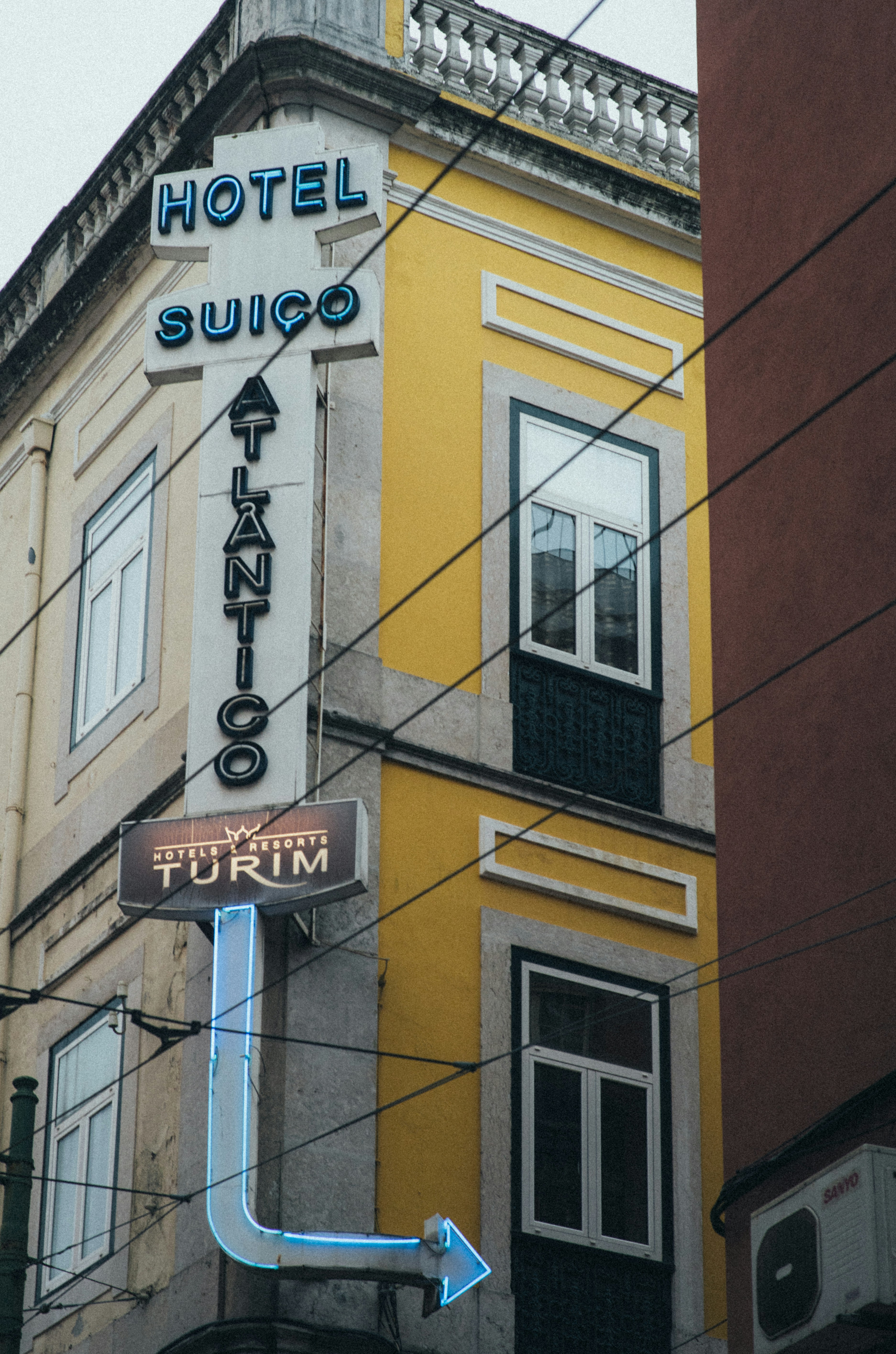 Atlanticico Neon on a Sunlit Yellow Hotel Facade