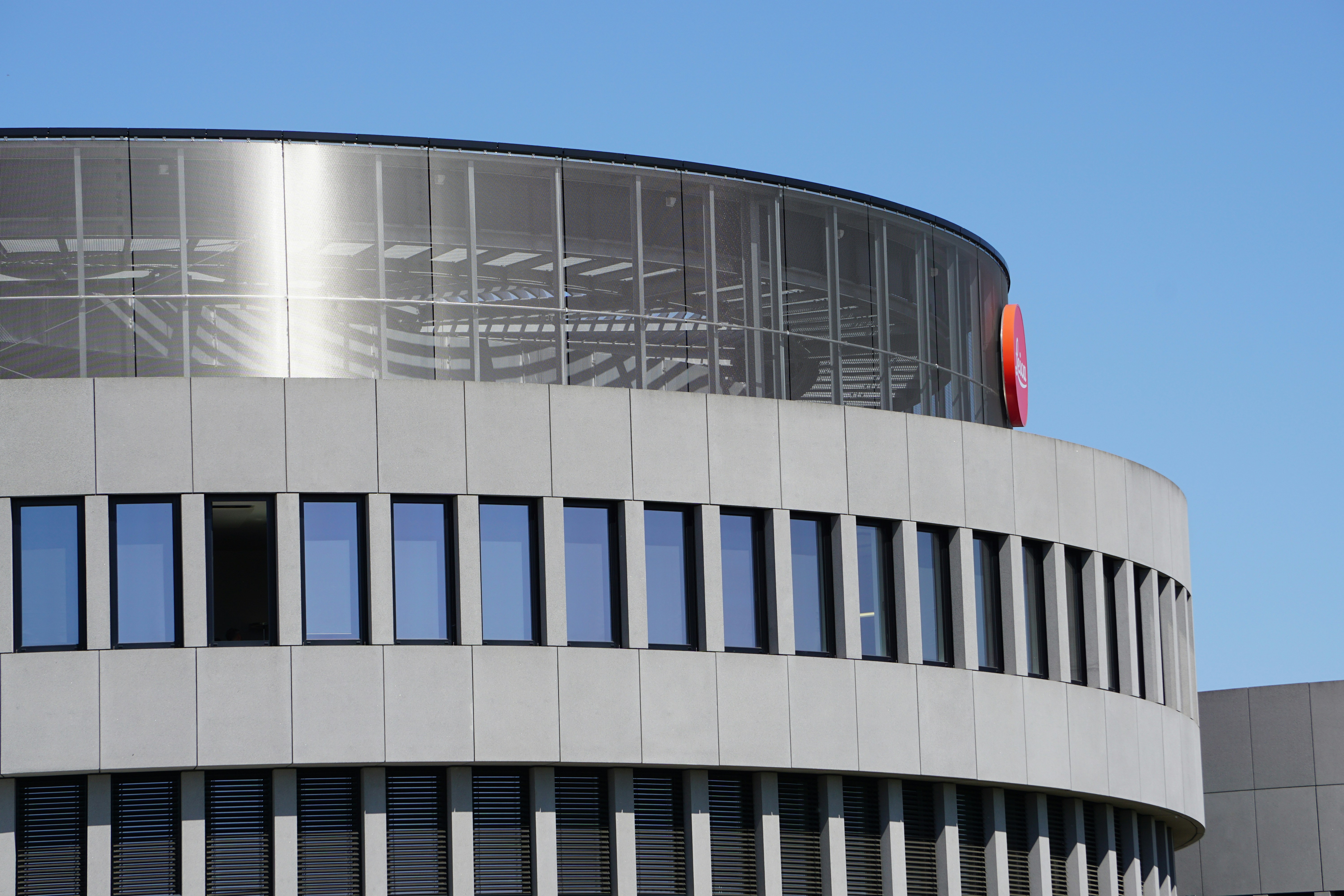 A sleek, modern building with a rounded roof and large windows, showcasing contemporary design elements against a clear blue sky.