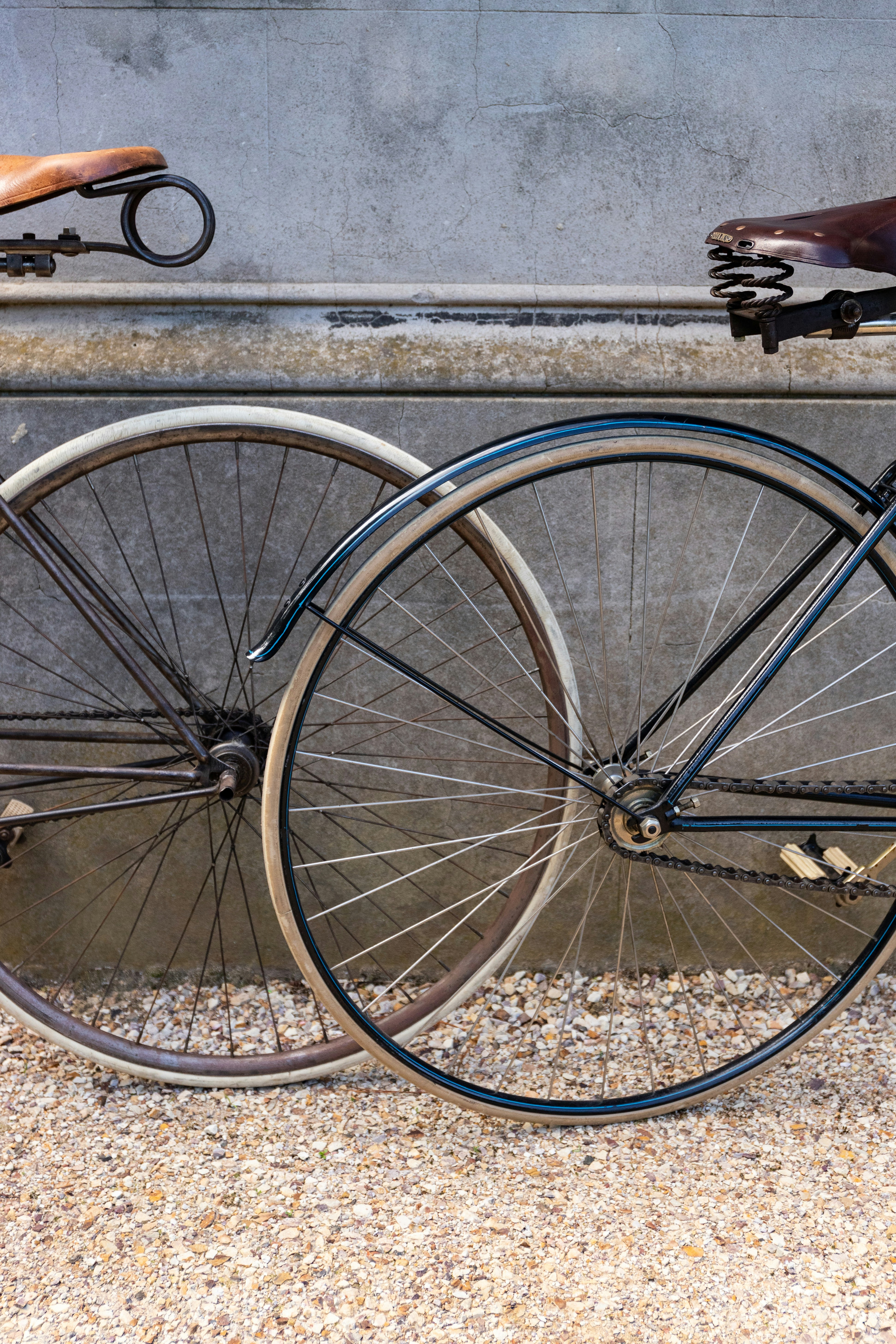 Two Vintage Bicycle Wheels Lean Against a Concrete Wall
