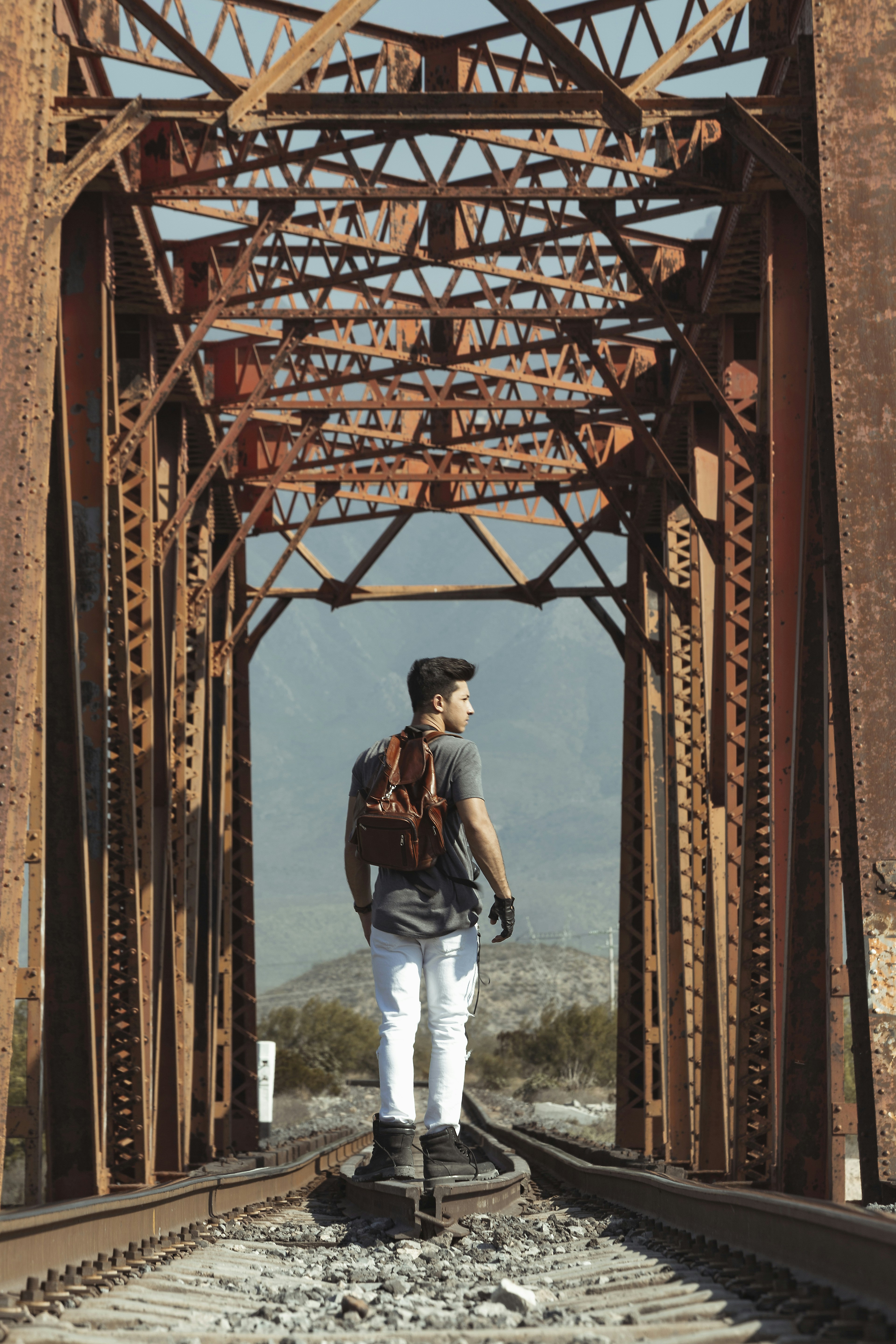Man in black t-shirt and blue denim jeans standing beside brown metal ...