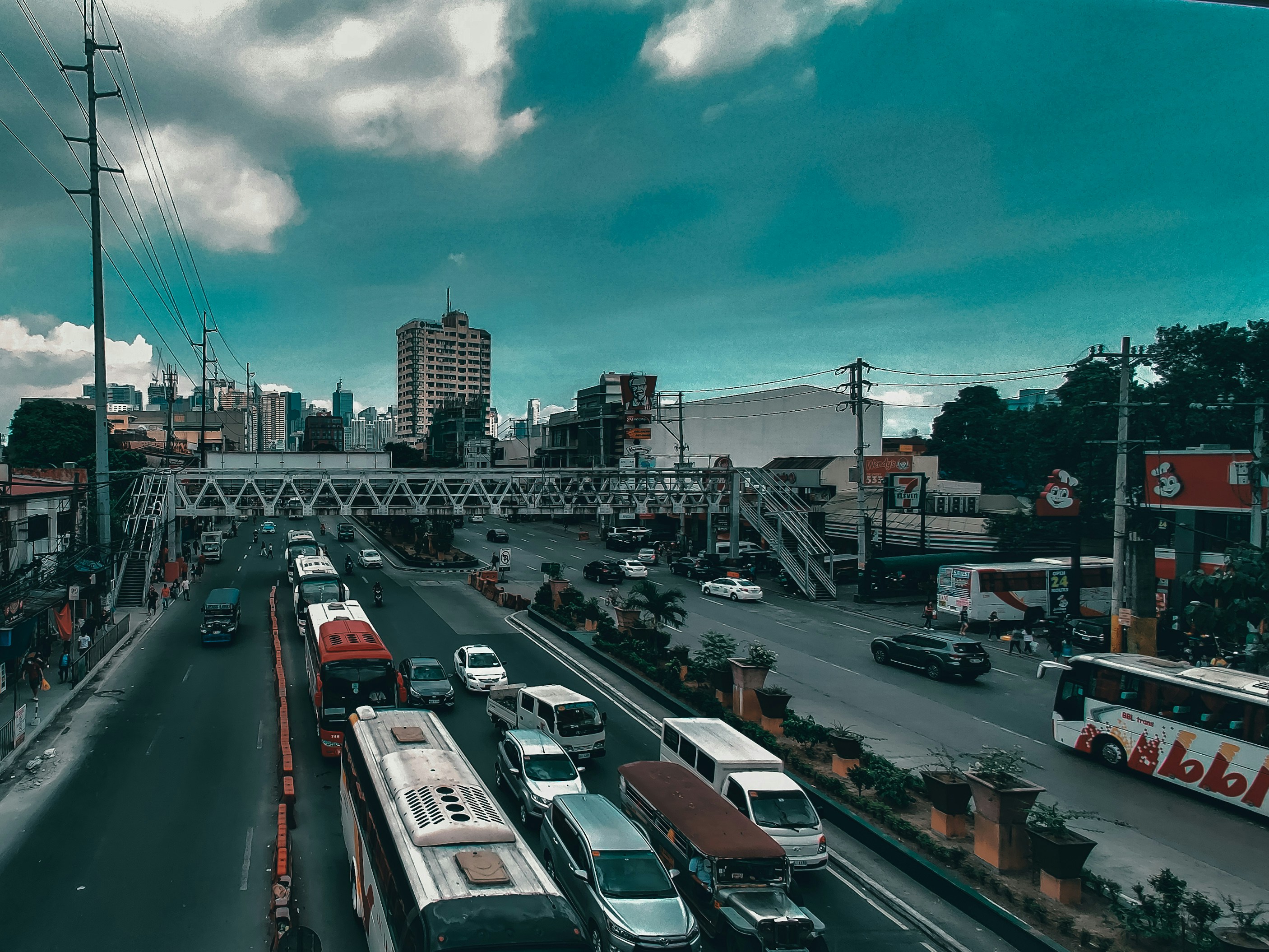 City traffic flows under an overcast sky with high-rise buildings in the background.