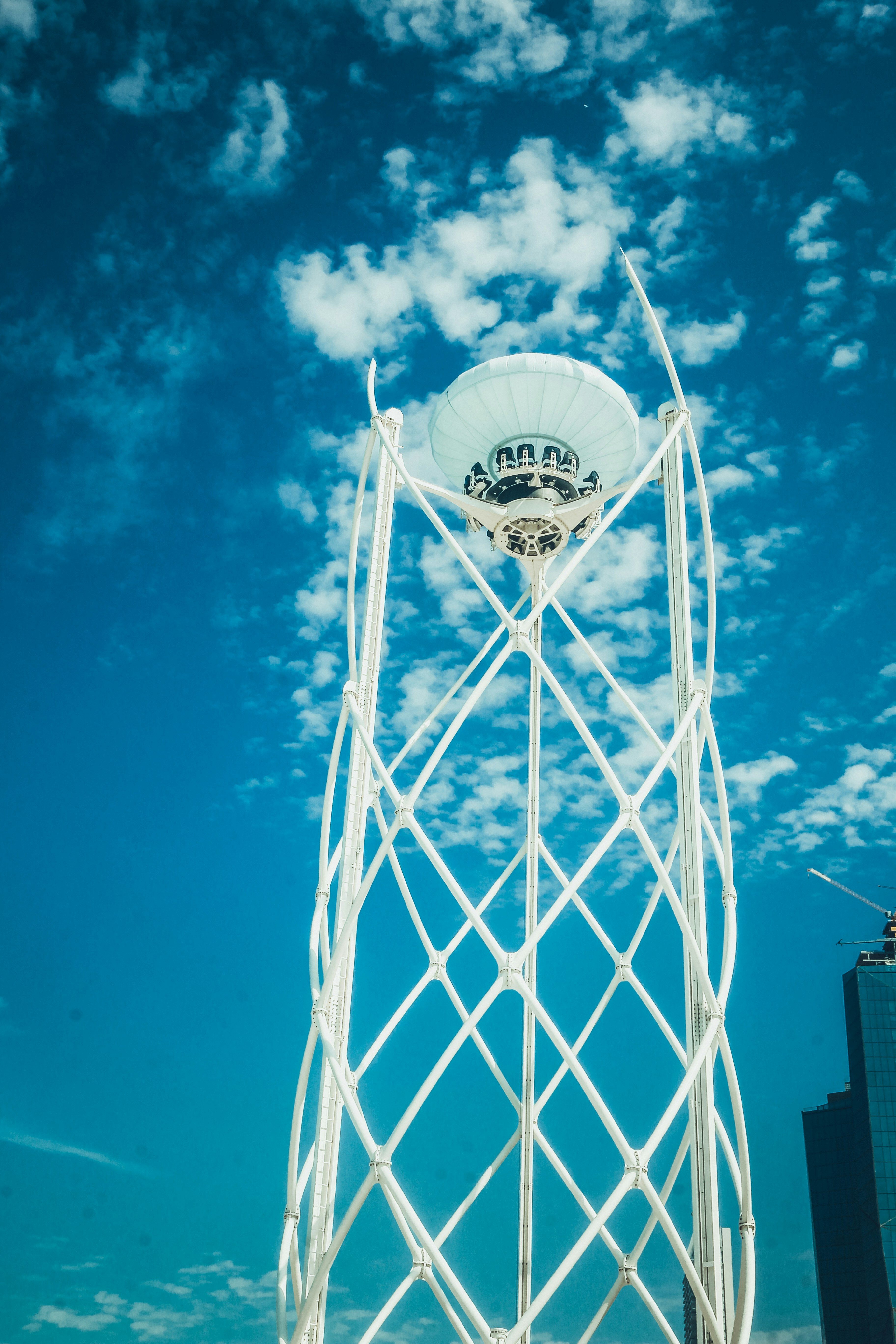 White lattice tower under a bright blue sky with a spherical beacon