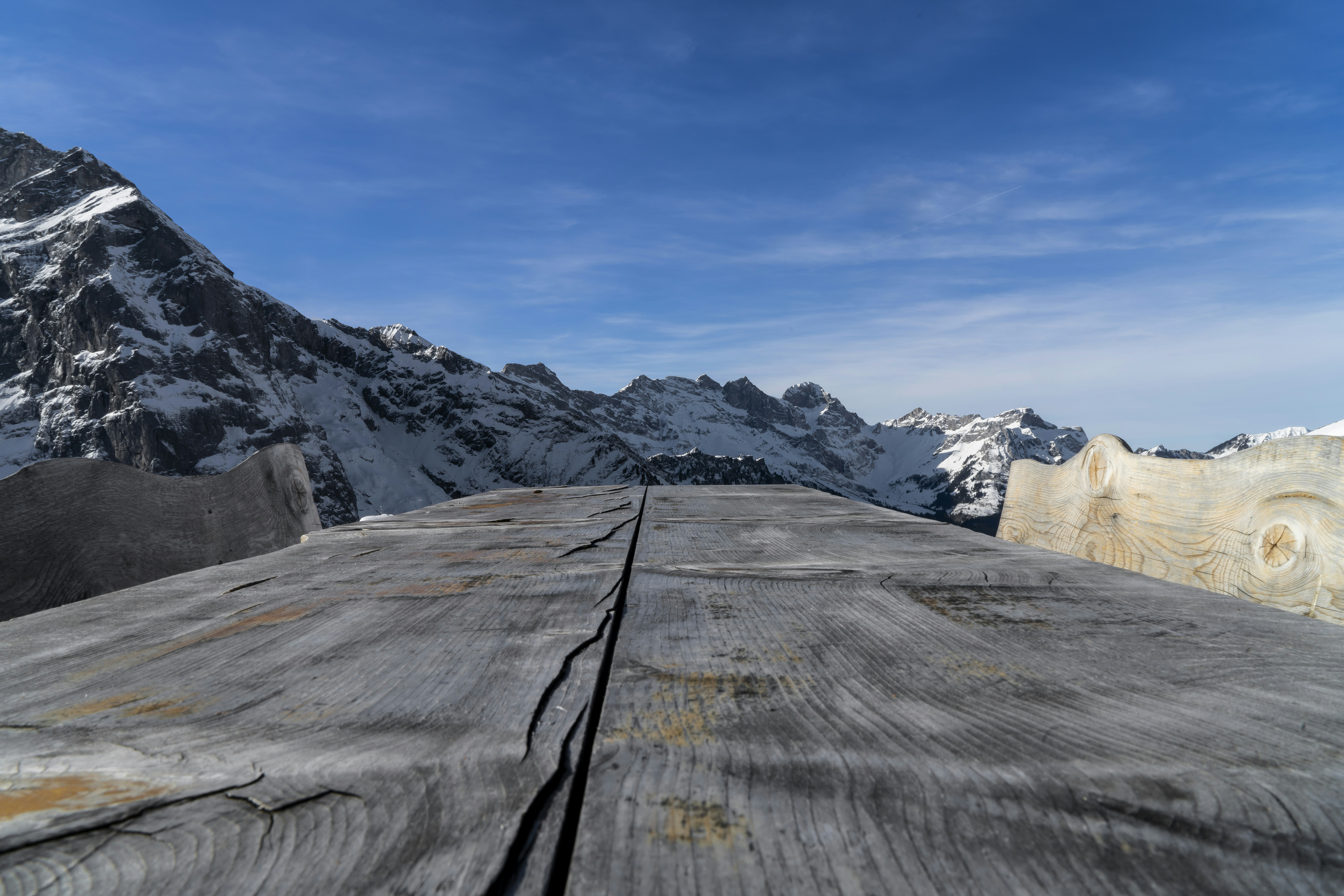 Cracked Timber Path Toward Snow-Capped Peaks