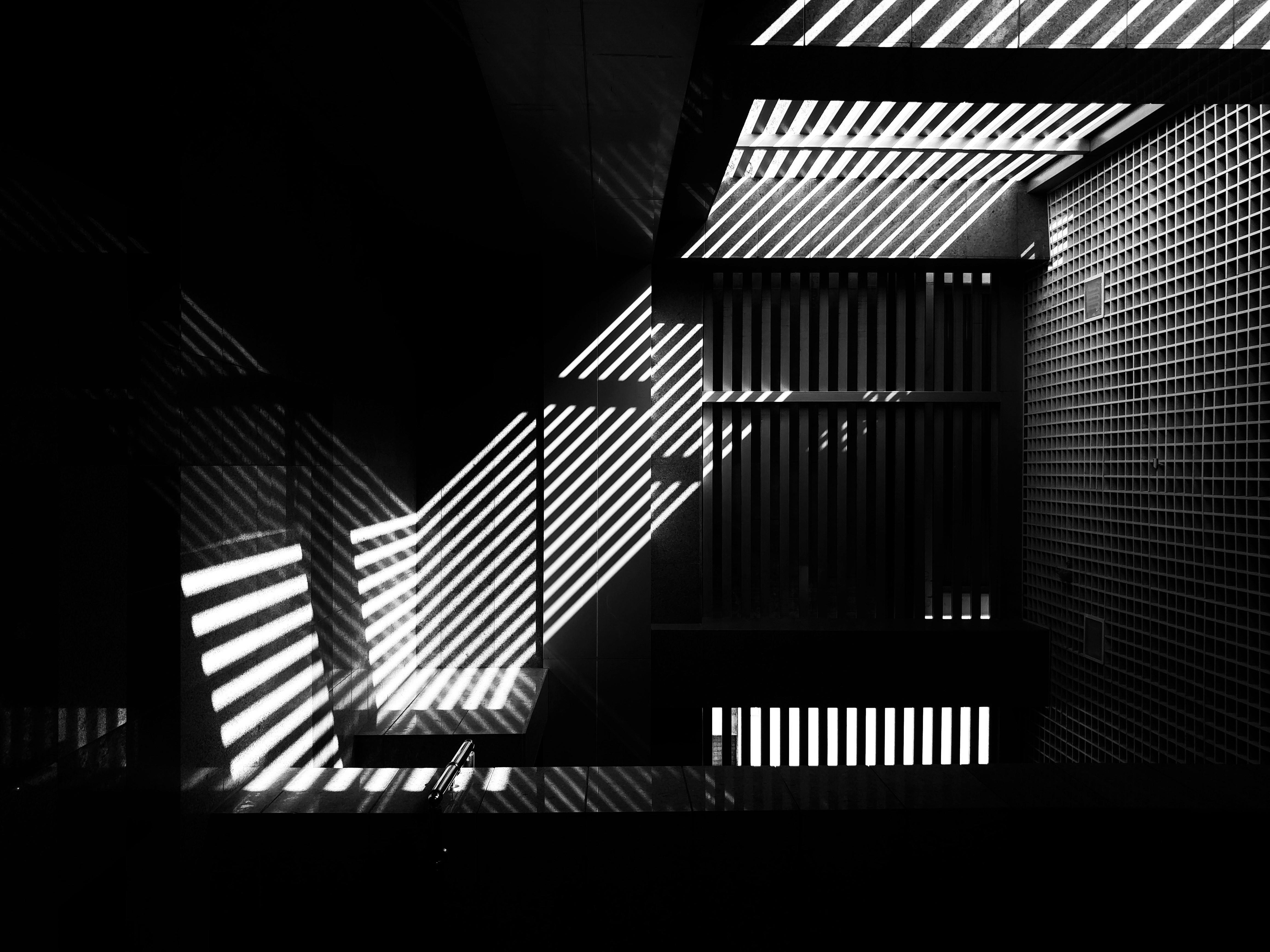 Black and white architectural structure with dramatic striped shadows creating geometric patterns.