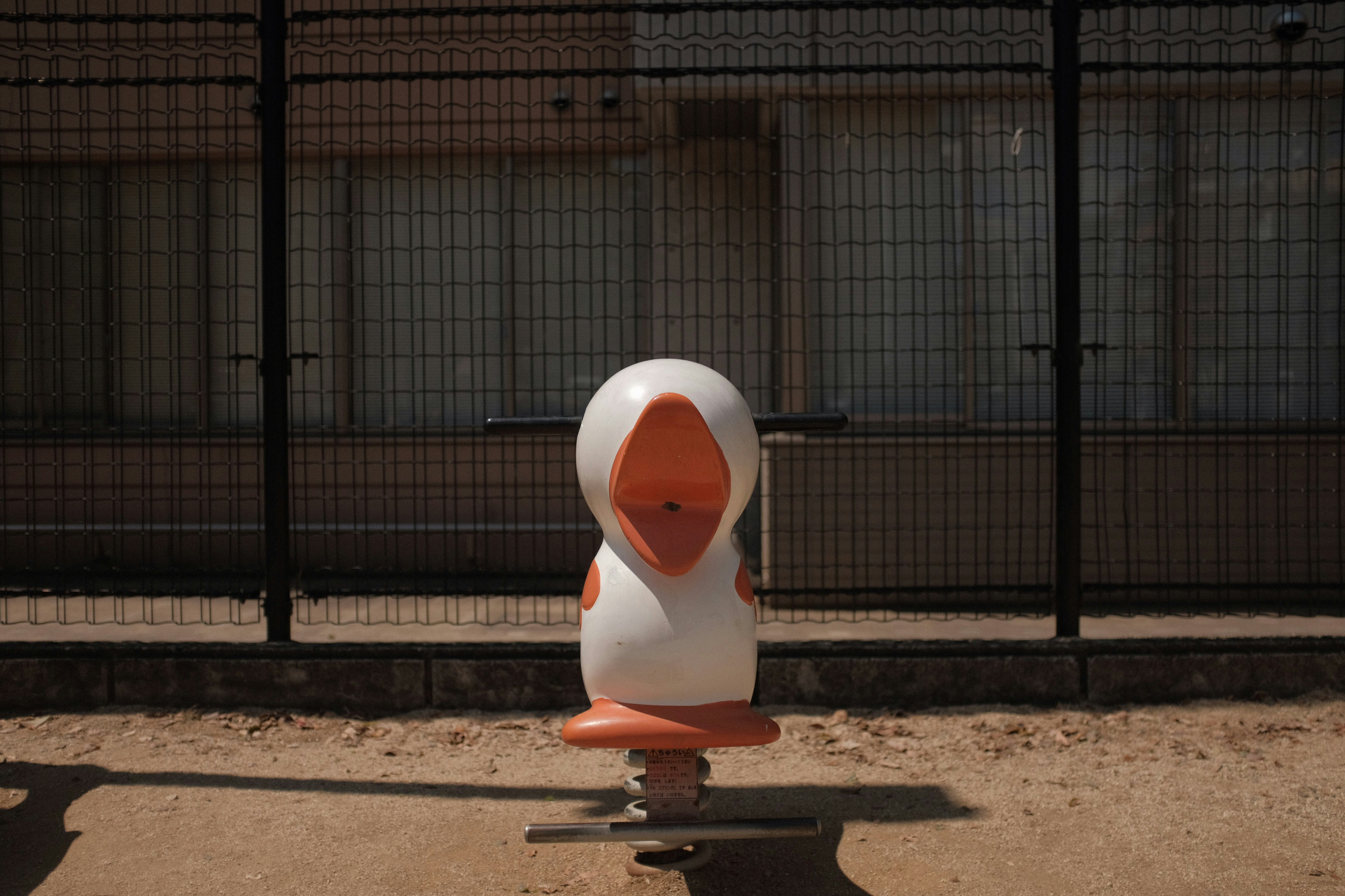 Solitary Orange-White Playground Seat: Centerpiece in a Fenced Yard