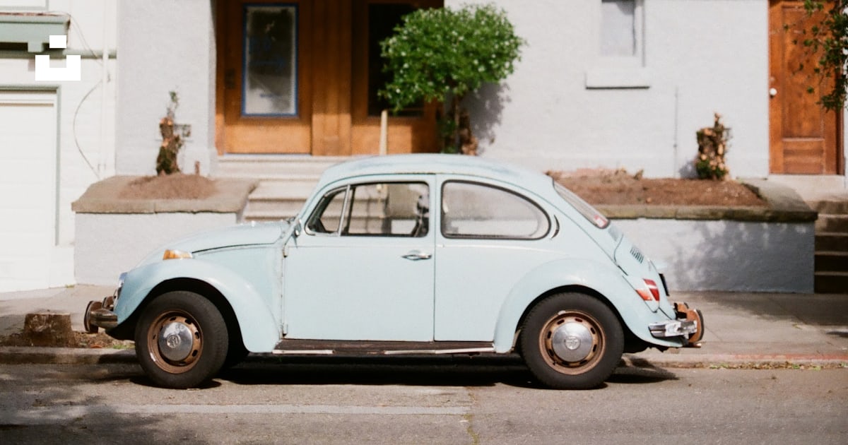 Blue Volkswagen Beetle Parked Beside White Concrete Building During