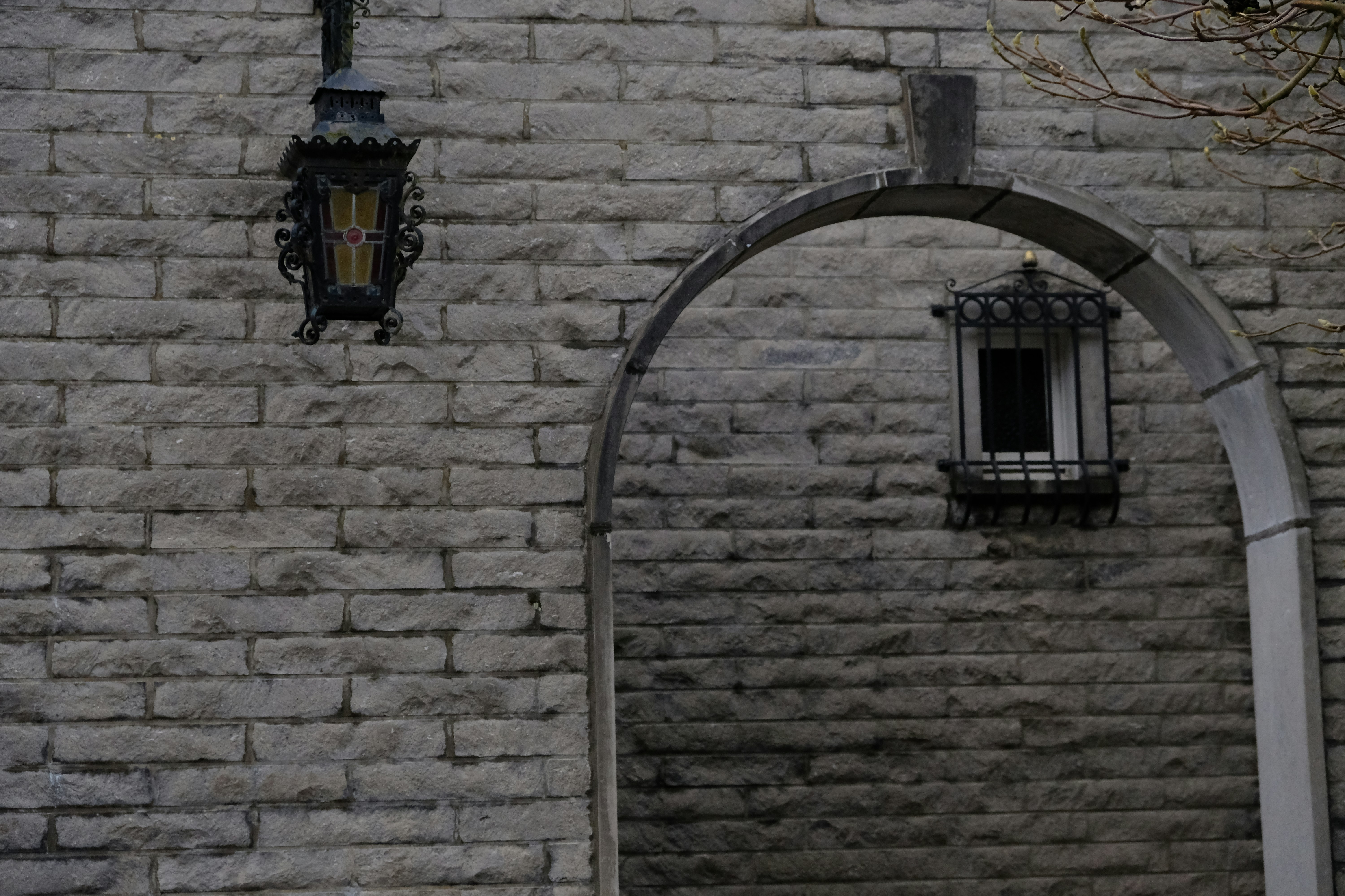 Stone Archway in Quiet Courtyard: Lanterned Wall Framed by a Gridded Window