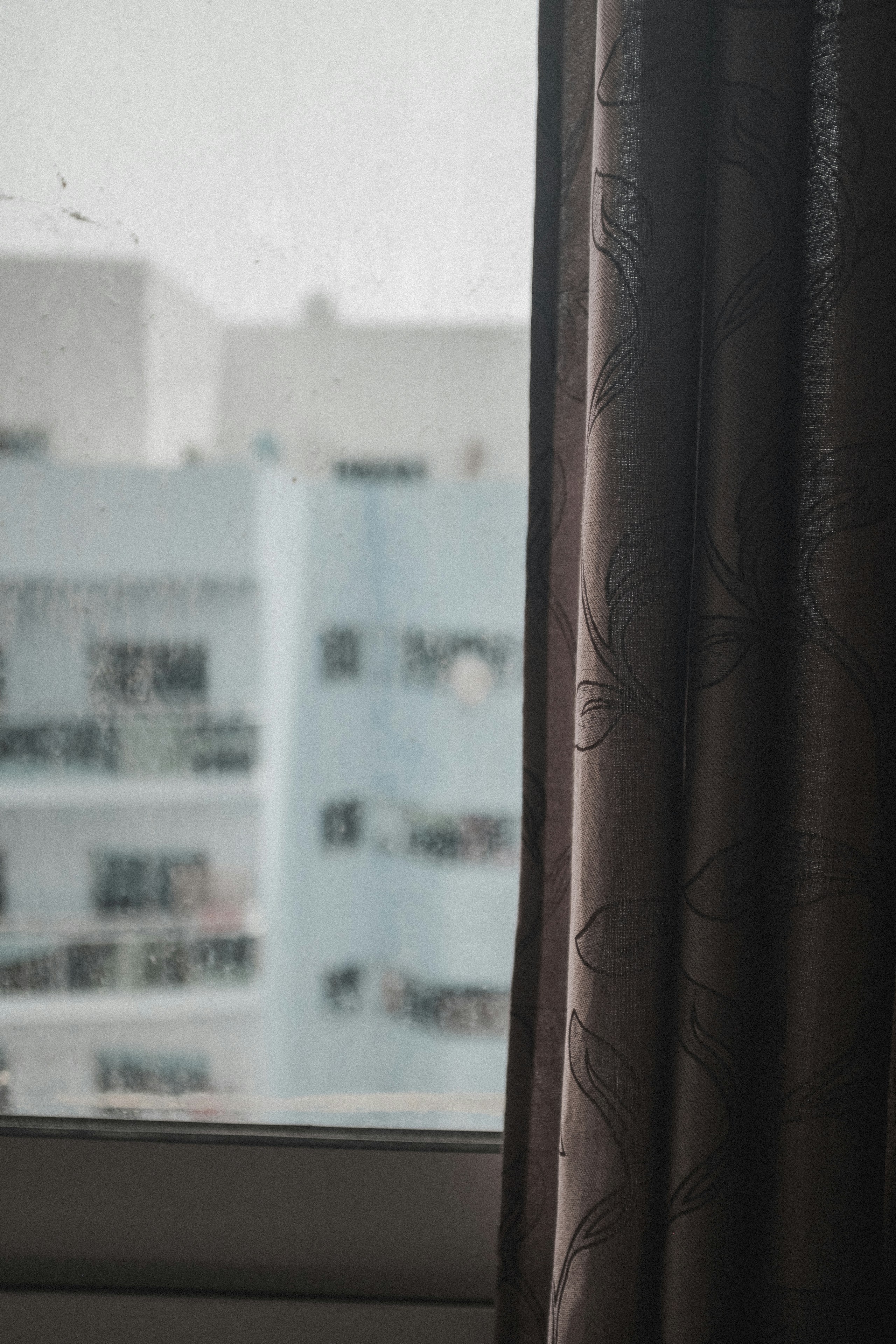 Curtain Edge Framing a Distant City in Soft Focus