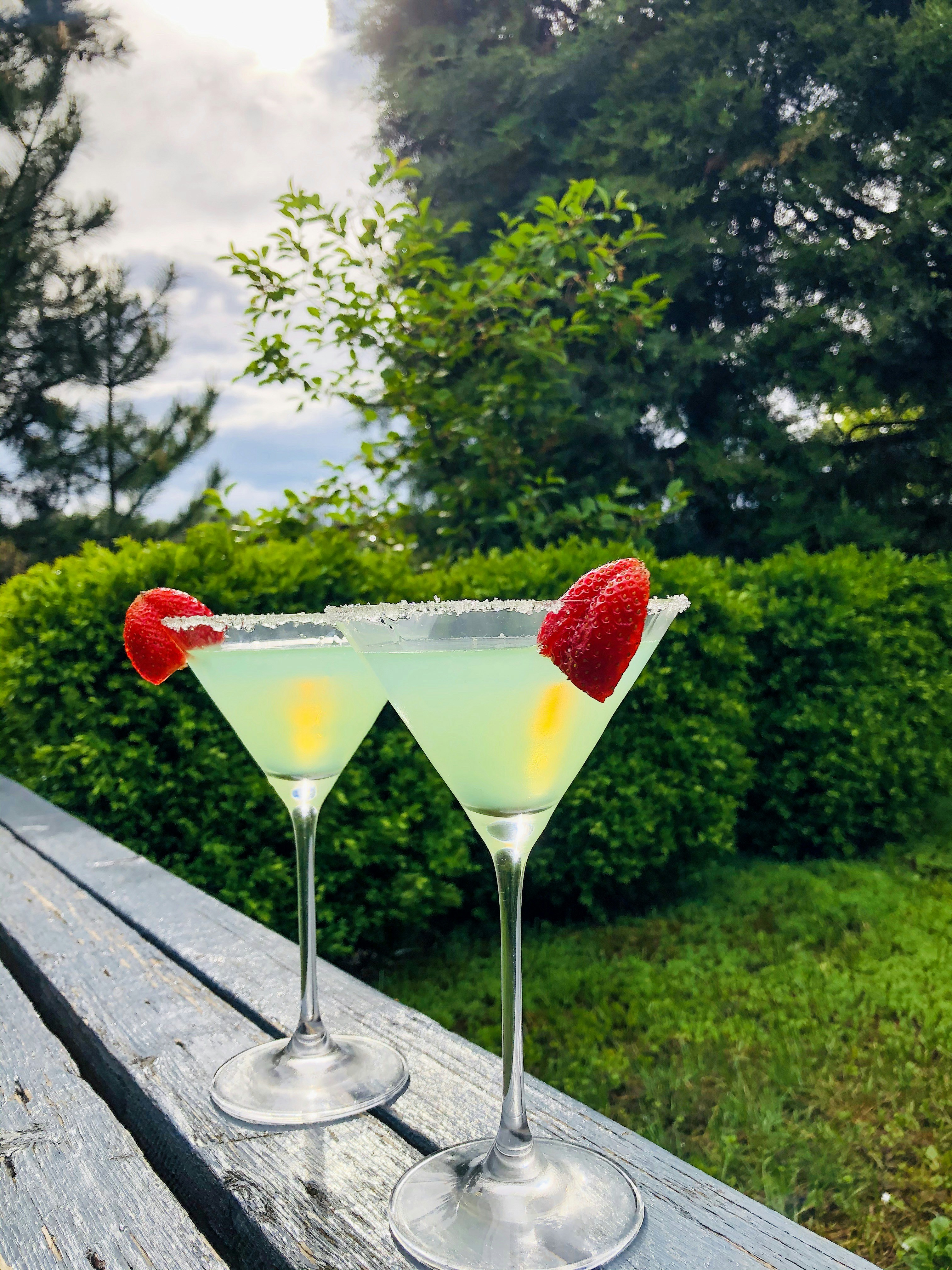 Two Lime-Green Margaritas on a Weathered Deck, Framed by Garden Greenery