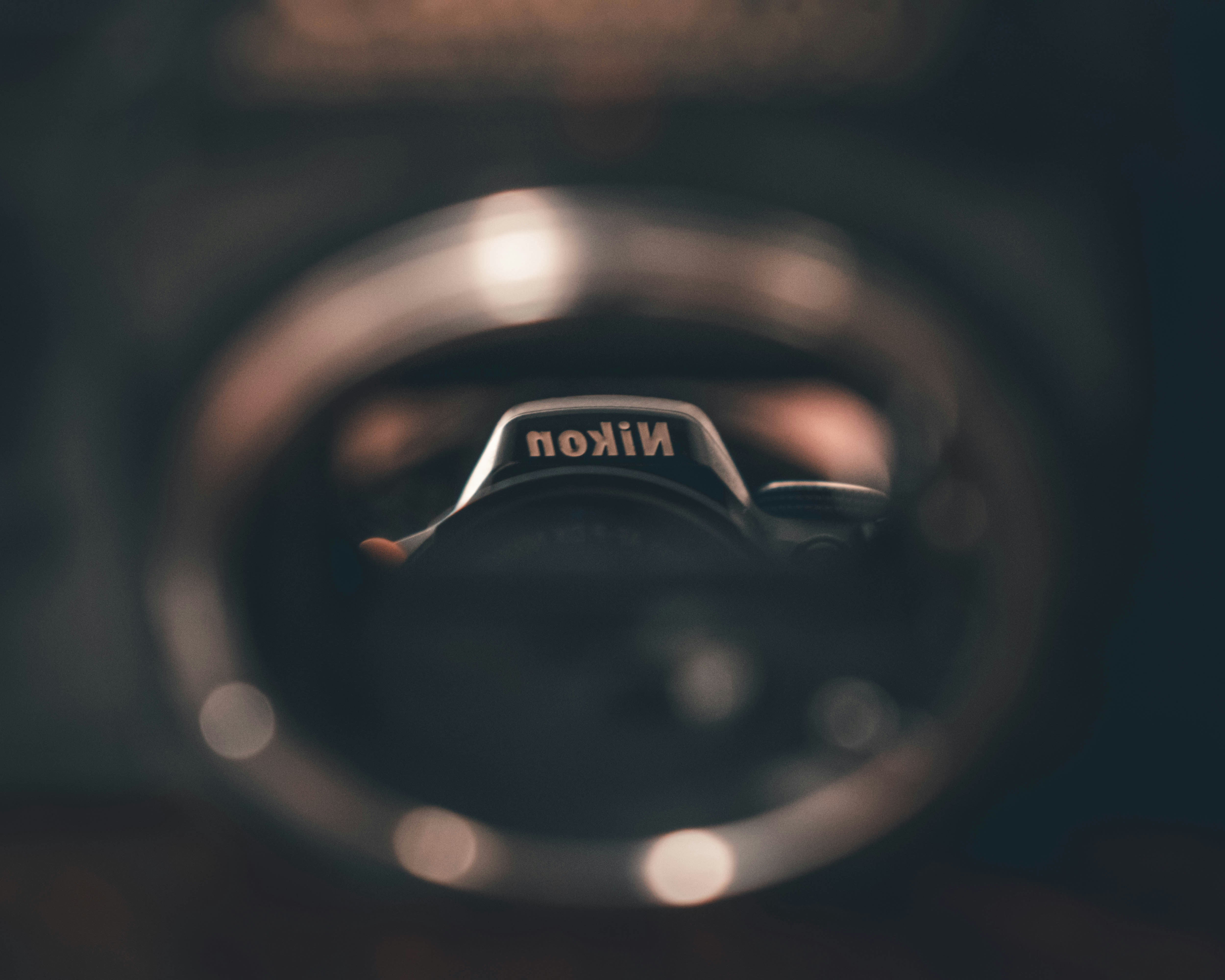 Close-up view of a Nikon camera body reflected in the lens of another camera, showcasing intricate details and craftsmanship.