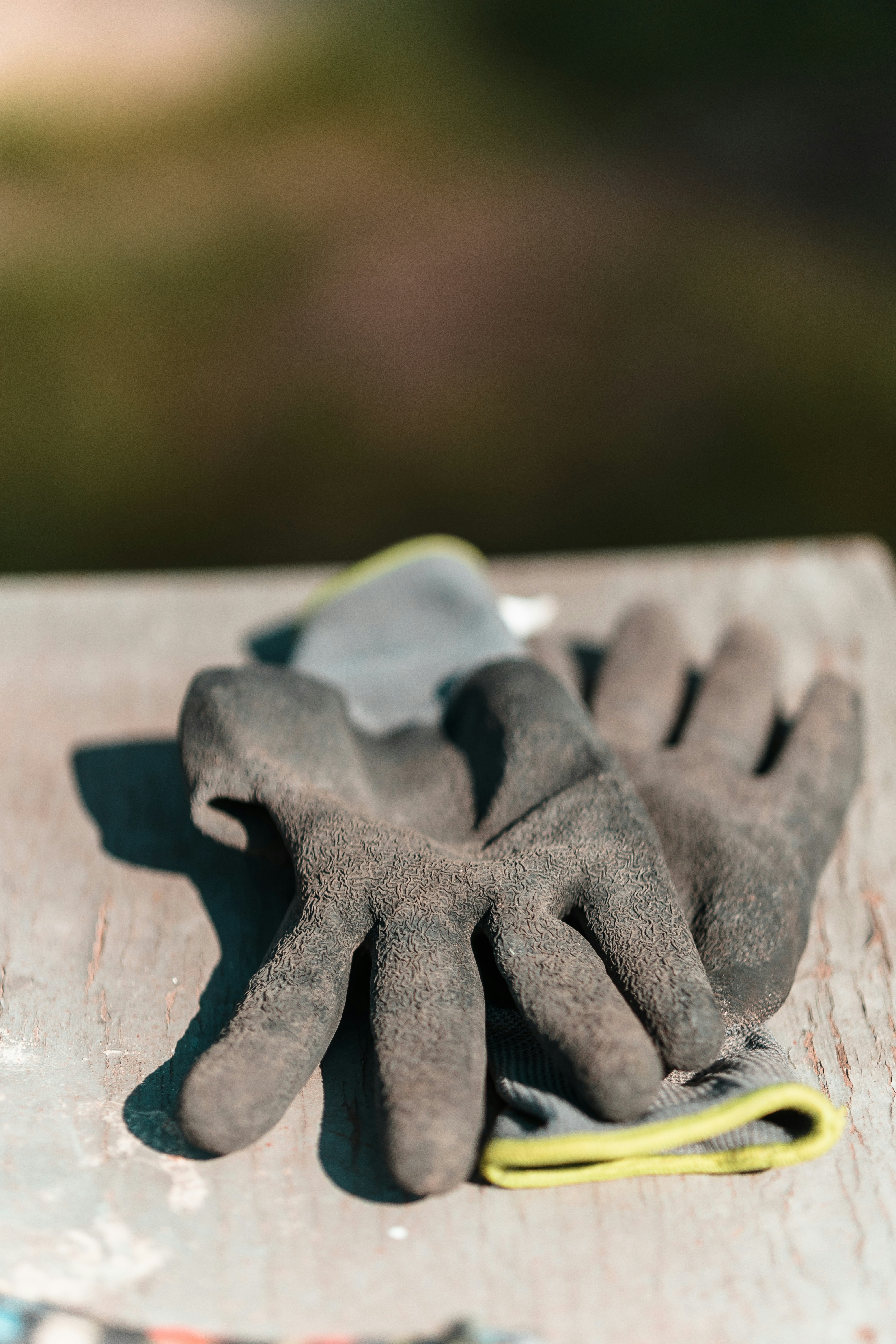 Worn gardening gloves resting on a weathered wooden surface, showcasing their texture and use. The scene evokes a sense of labor and care.