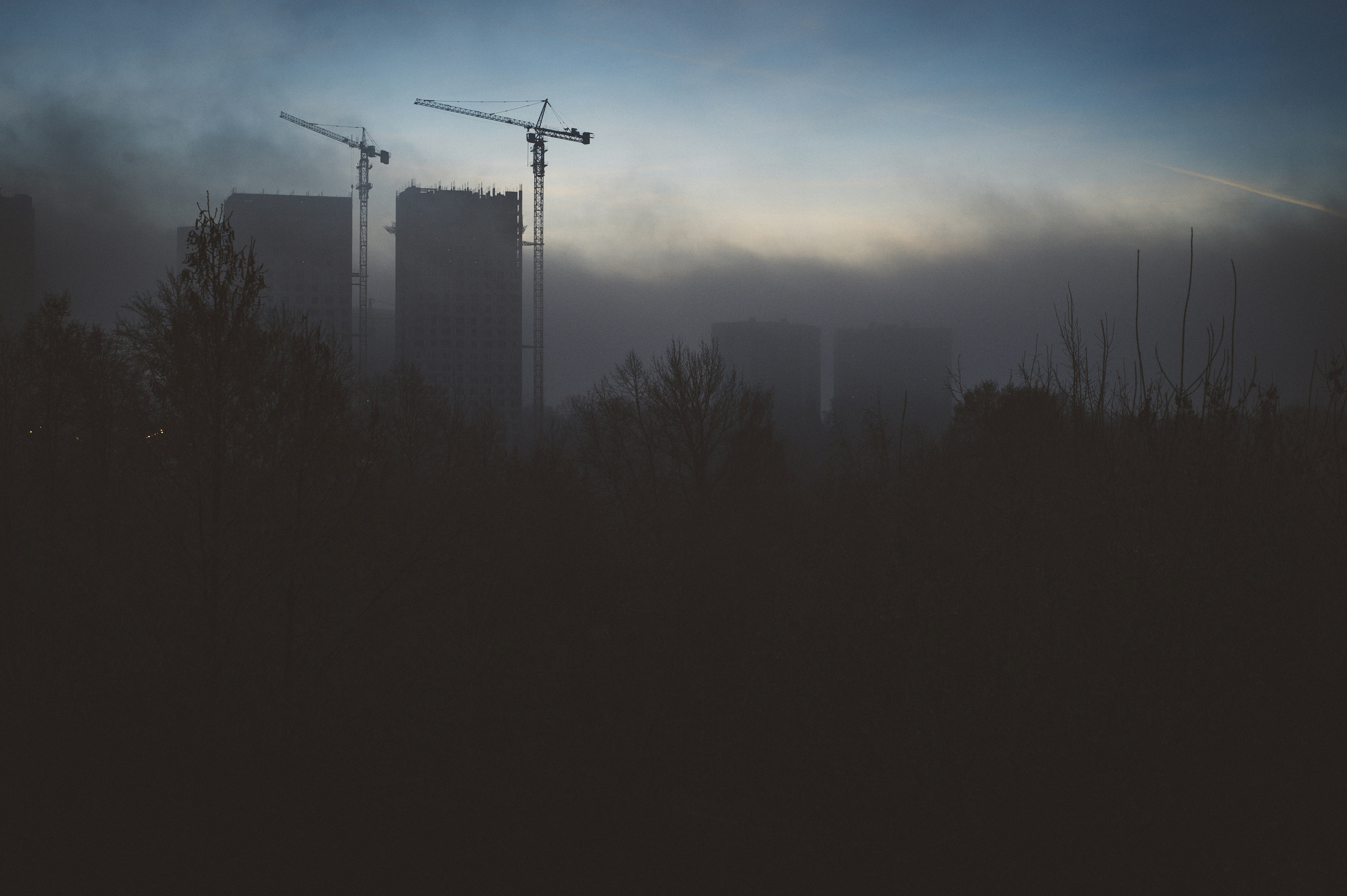 Dawn Skyline in Mist: Crane silhouettes Over a Quiet Industrial Edge