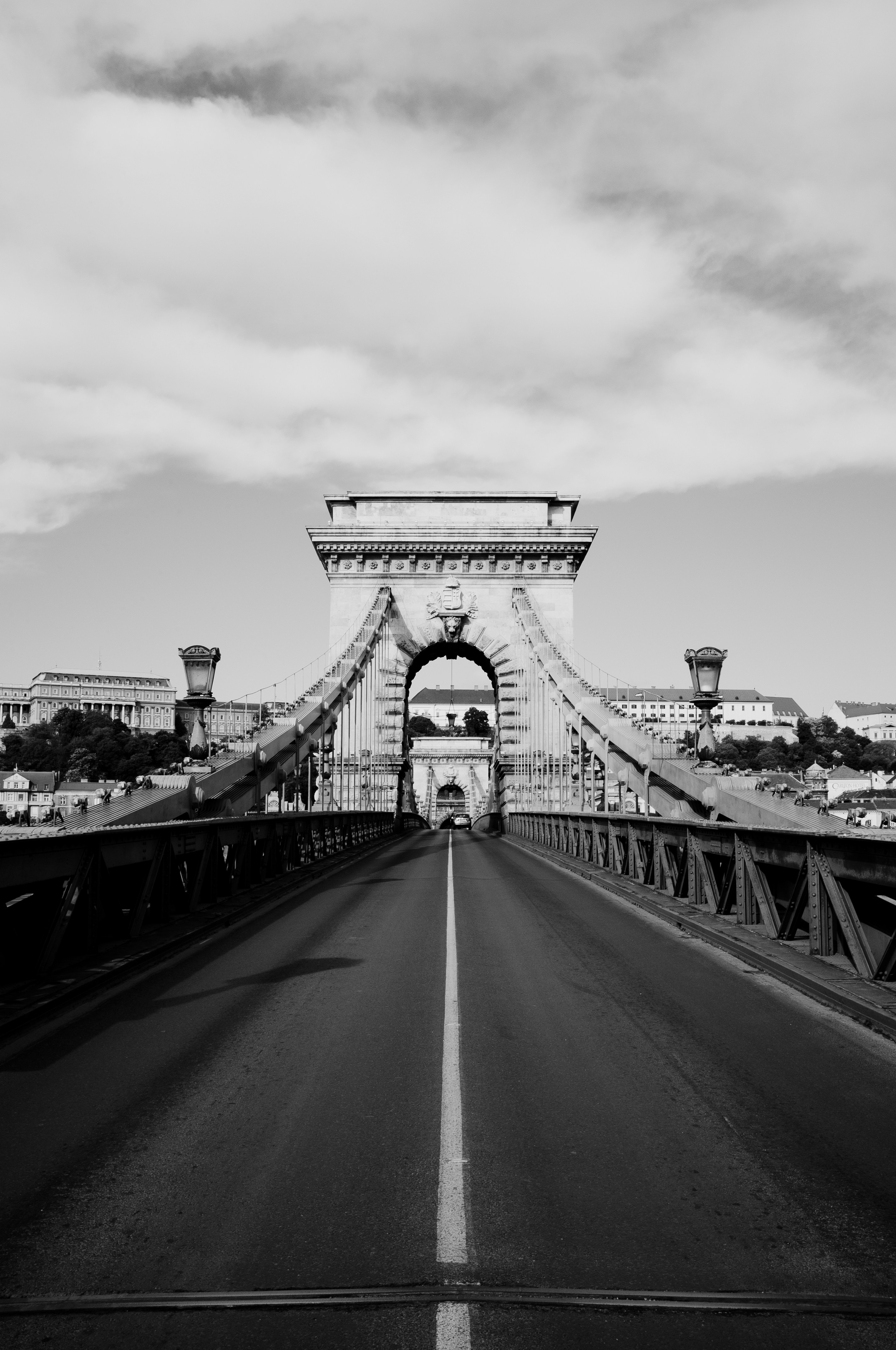 grayscale photo of bridge under cloudy sky
