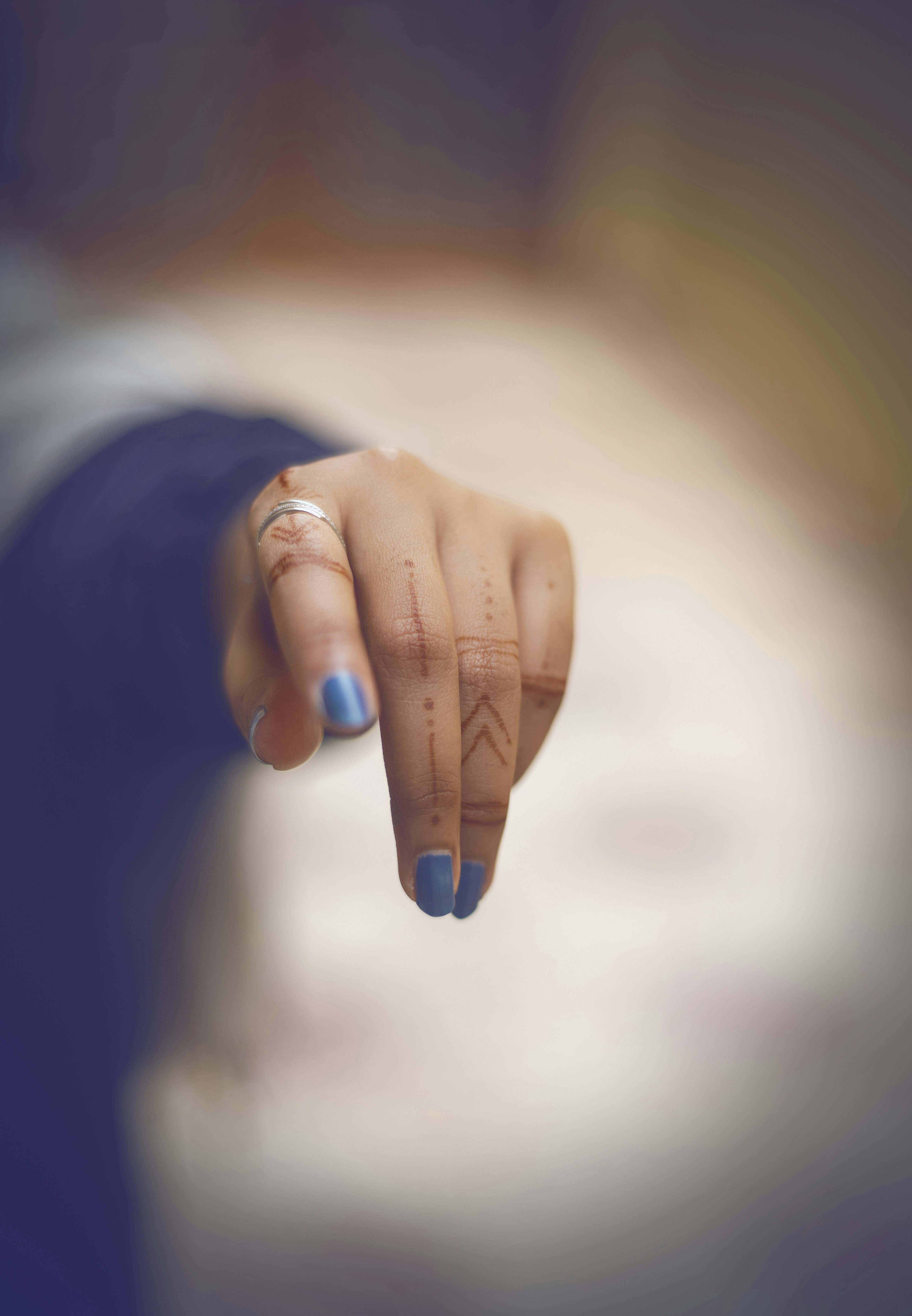 Blue-Nail Pointer in Velvet Blur: Close-Up of Hand with Decorative Marks