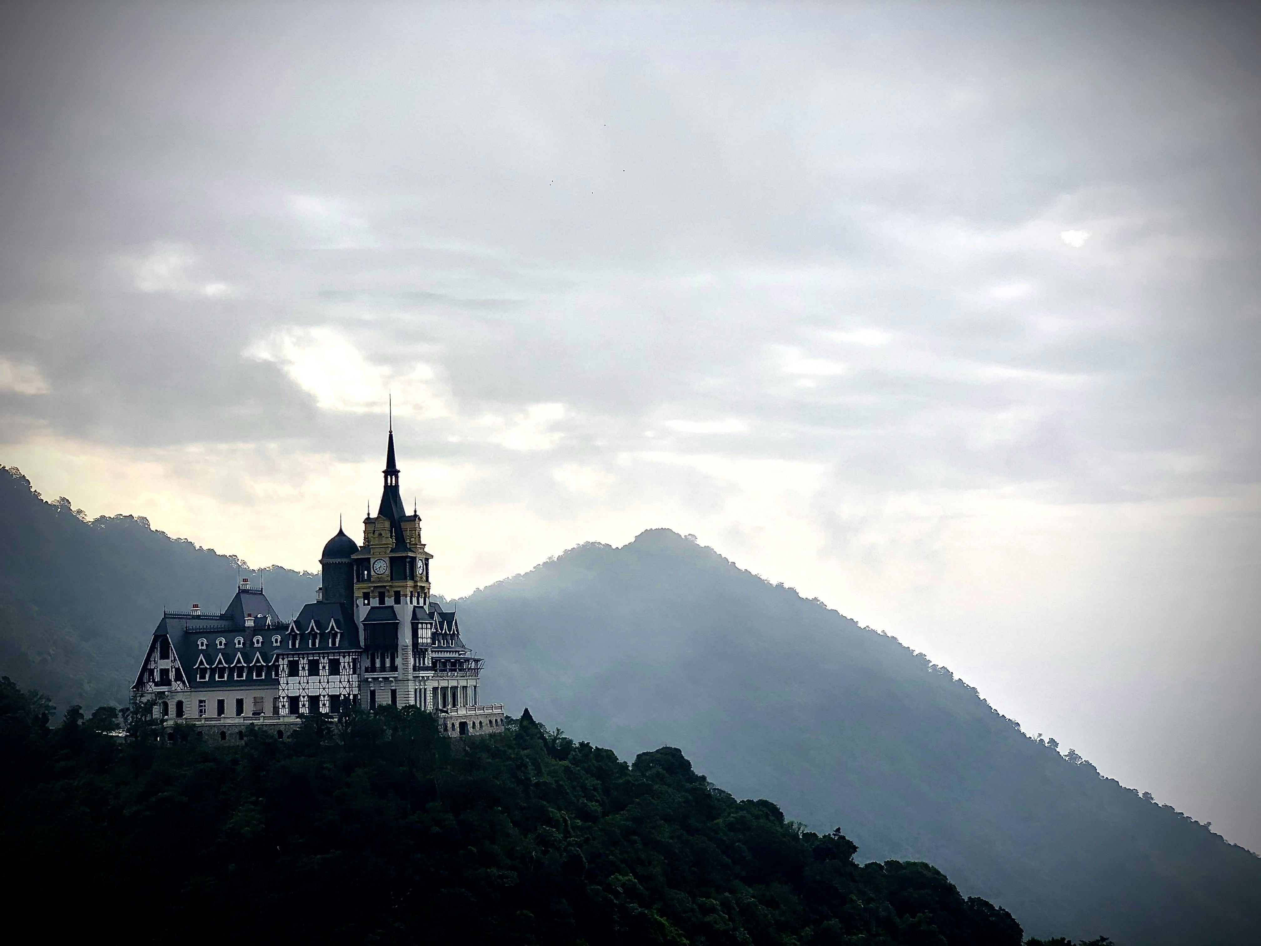 A majestic castle perched atop a lush mountain, shrouded in mist and mystery. The architecture blends harmoniously with the surrounding landscape.
