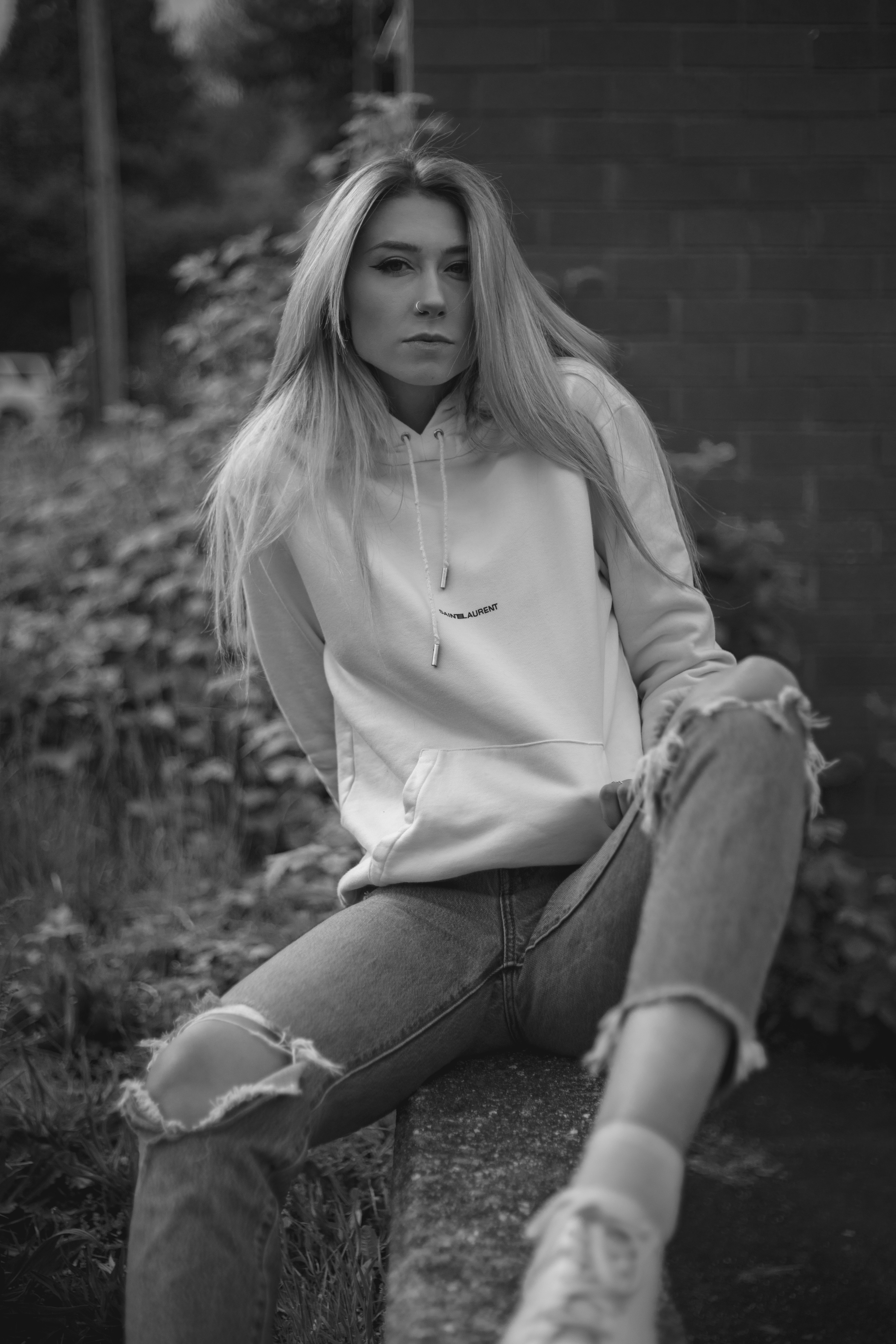 Monochrome Quietude: A Portrait Framed by Brick and Greenery