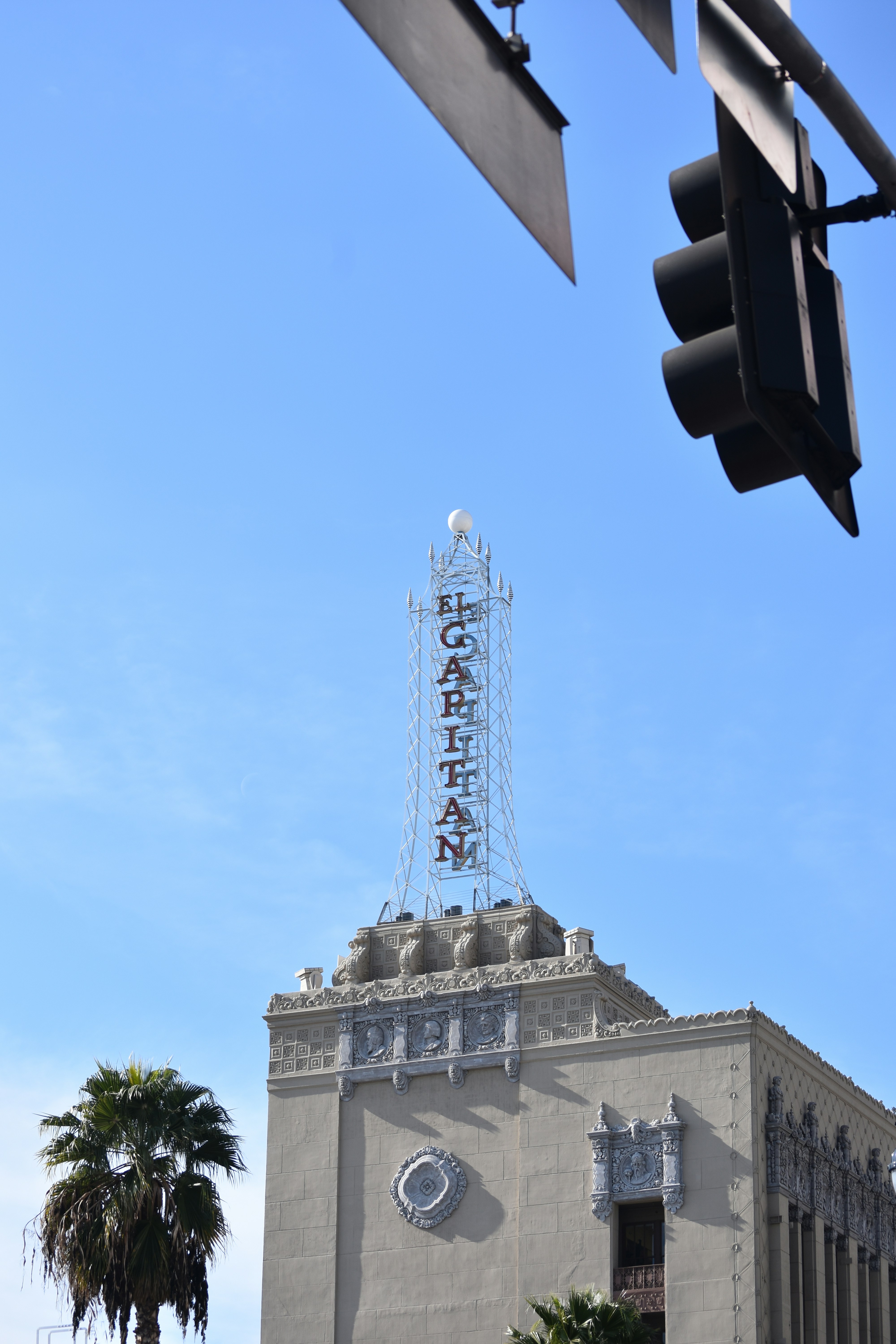Historic El Garitan theater sign towering above a palm tree against a clear blue sky.