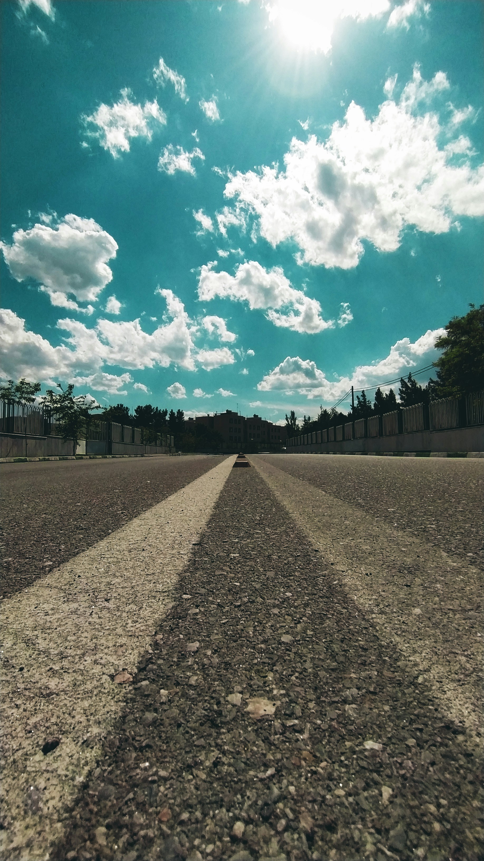 Low-Angle Road to Sky: Sunlit Asphalt Converging Toward a Distant Building