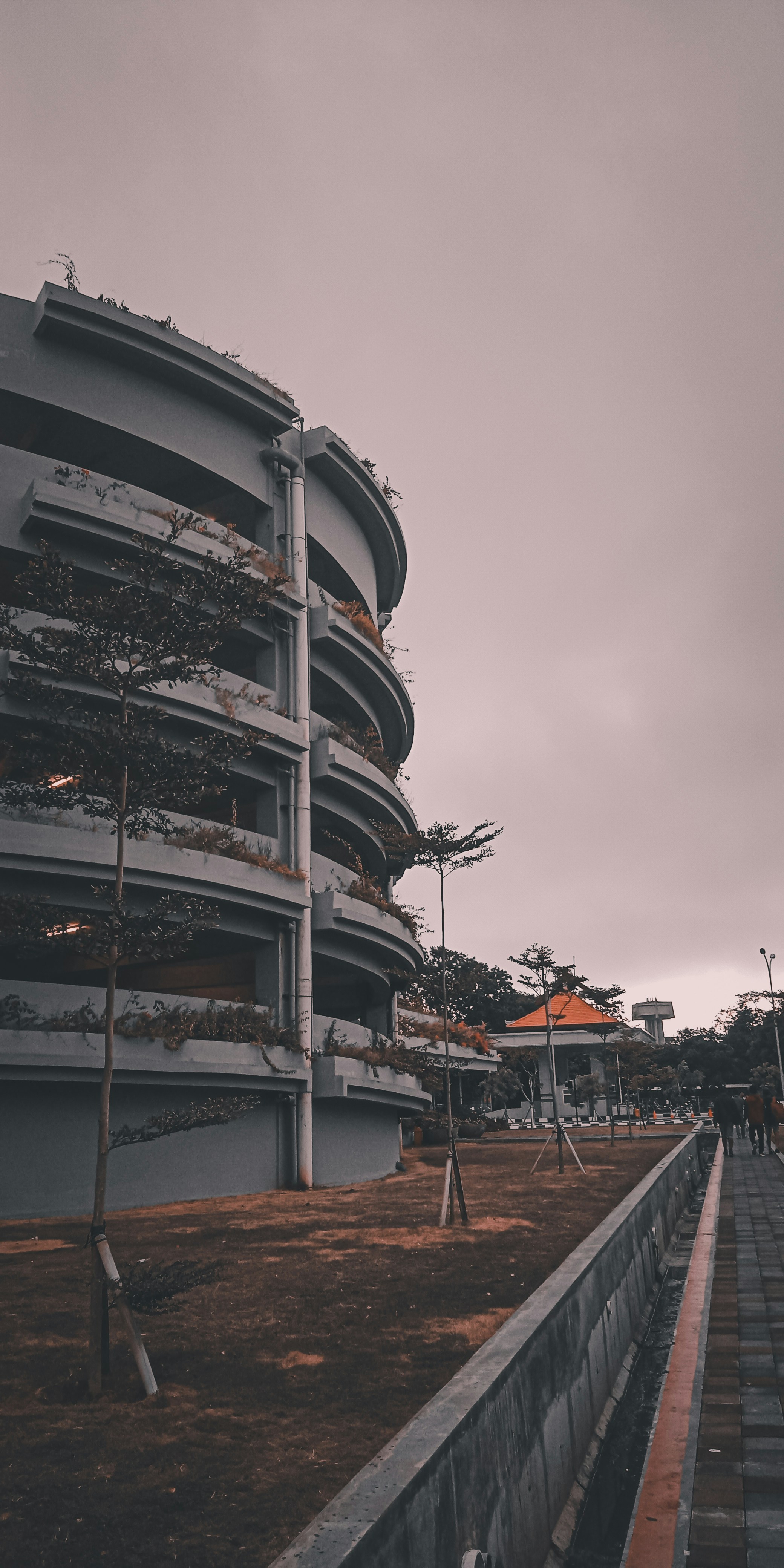 Curved modern building with surrounding trees under a muted sky.