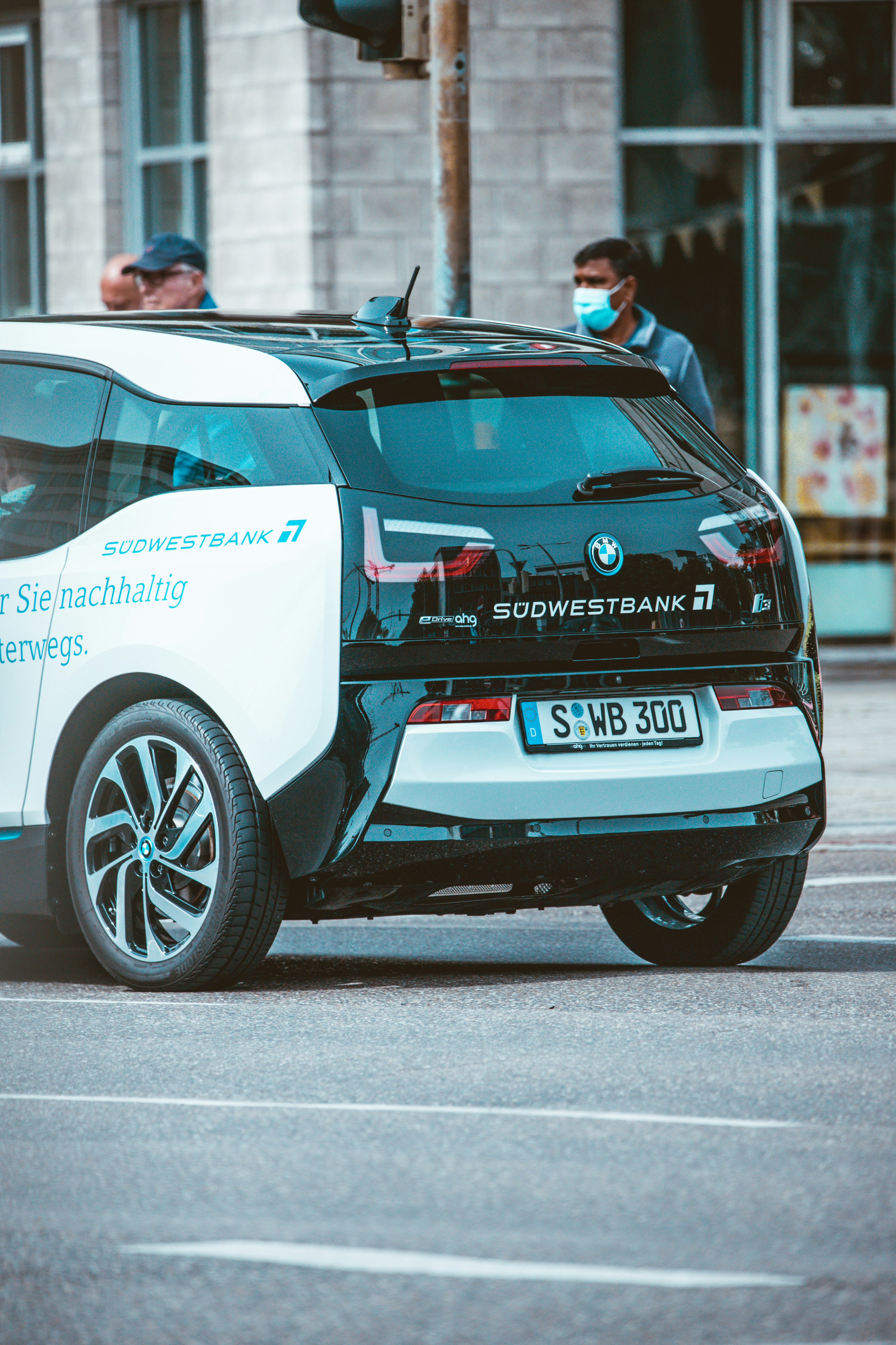 SODWESTBANK BMW i3 at a city intersection with masked pedestrians nearby